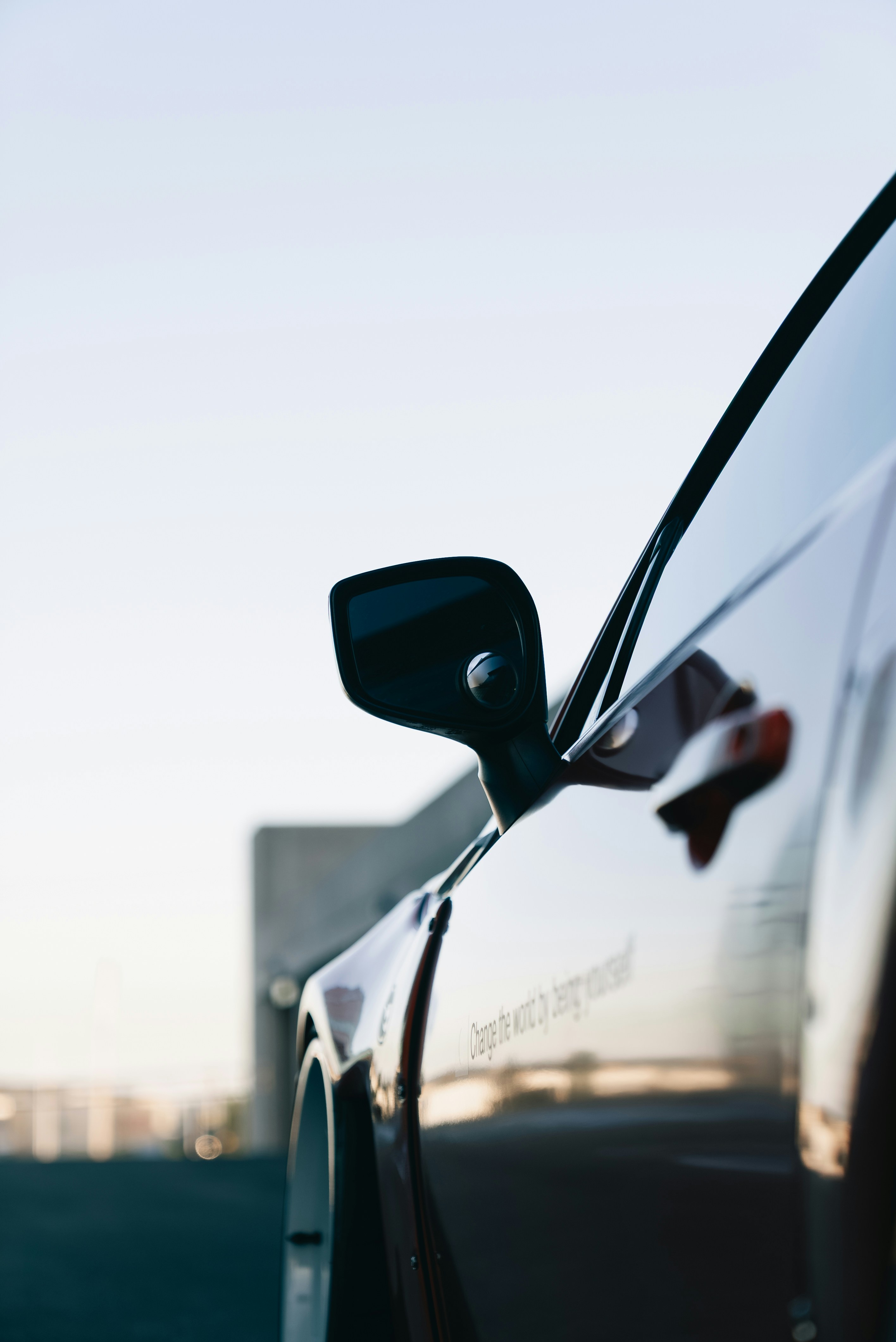 Side Mirror in Focus: A Sharp Glimpse of a Car's Silhouette at Dusk