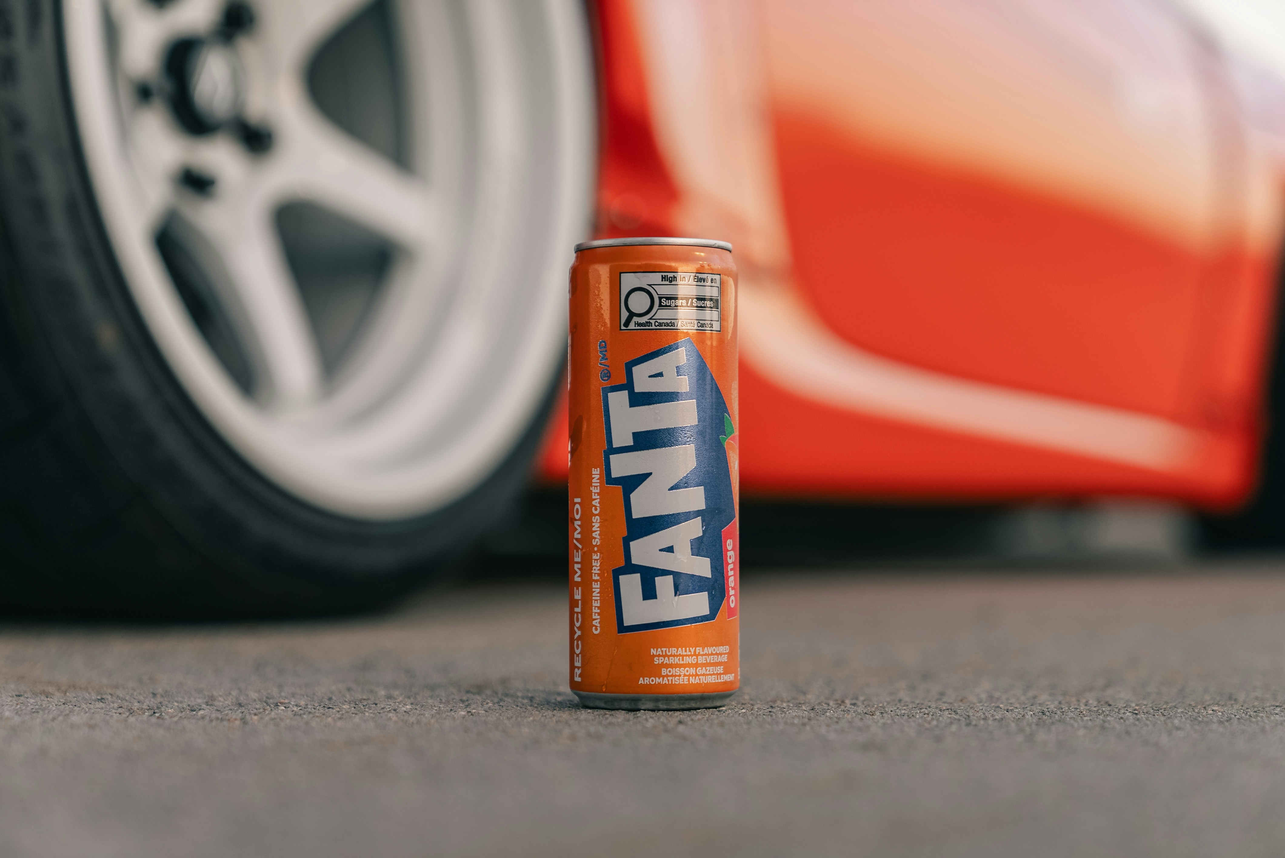 Orange Fizz in Focus: A Fanta can Stands firm on the Asphalt