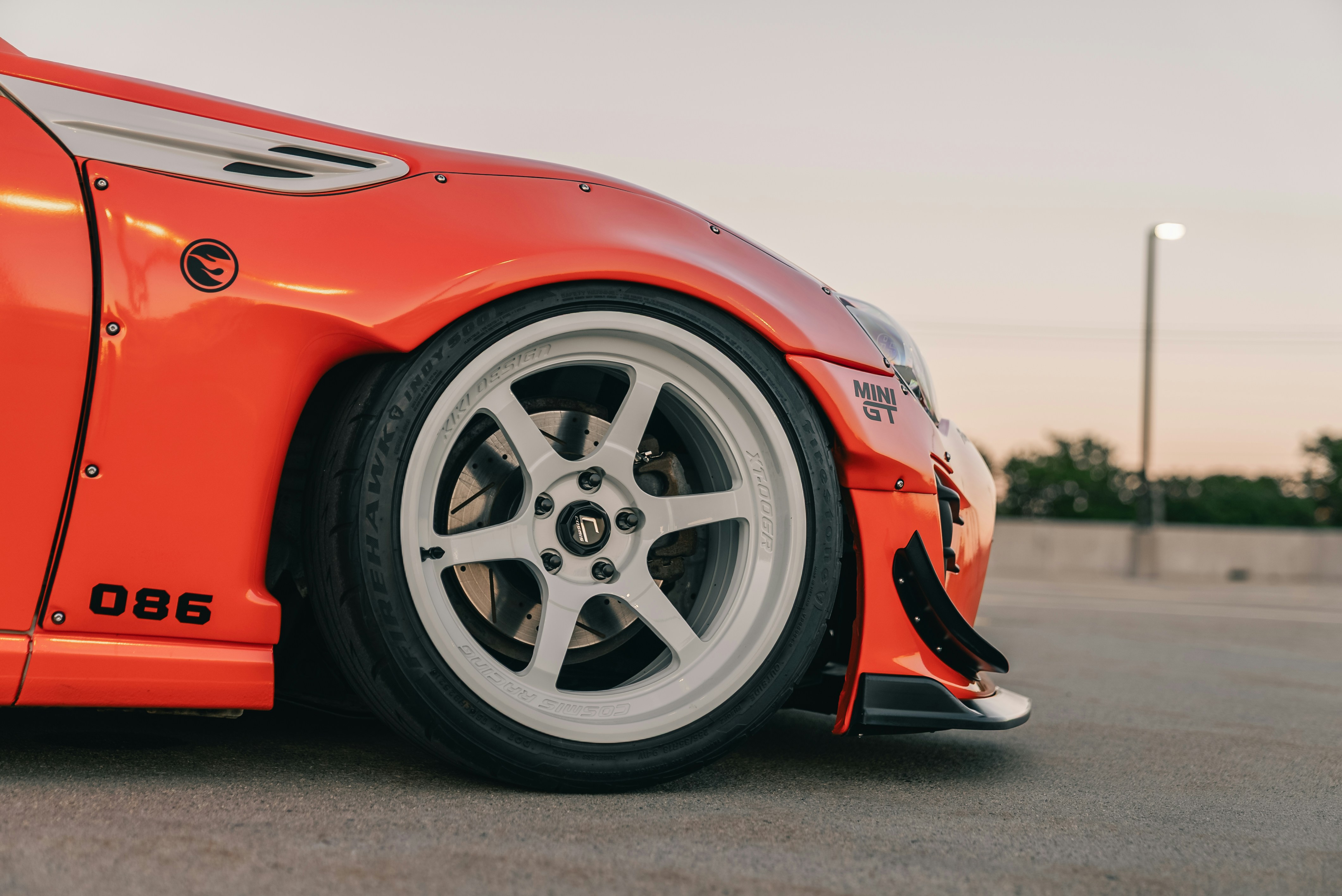 Low-angle close-up: orange race car wheel with exposed brake and tire curvature