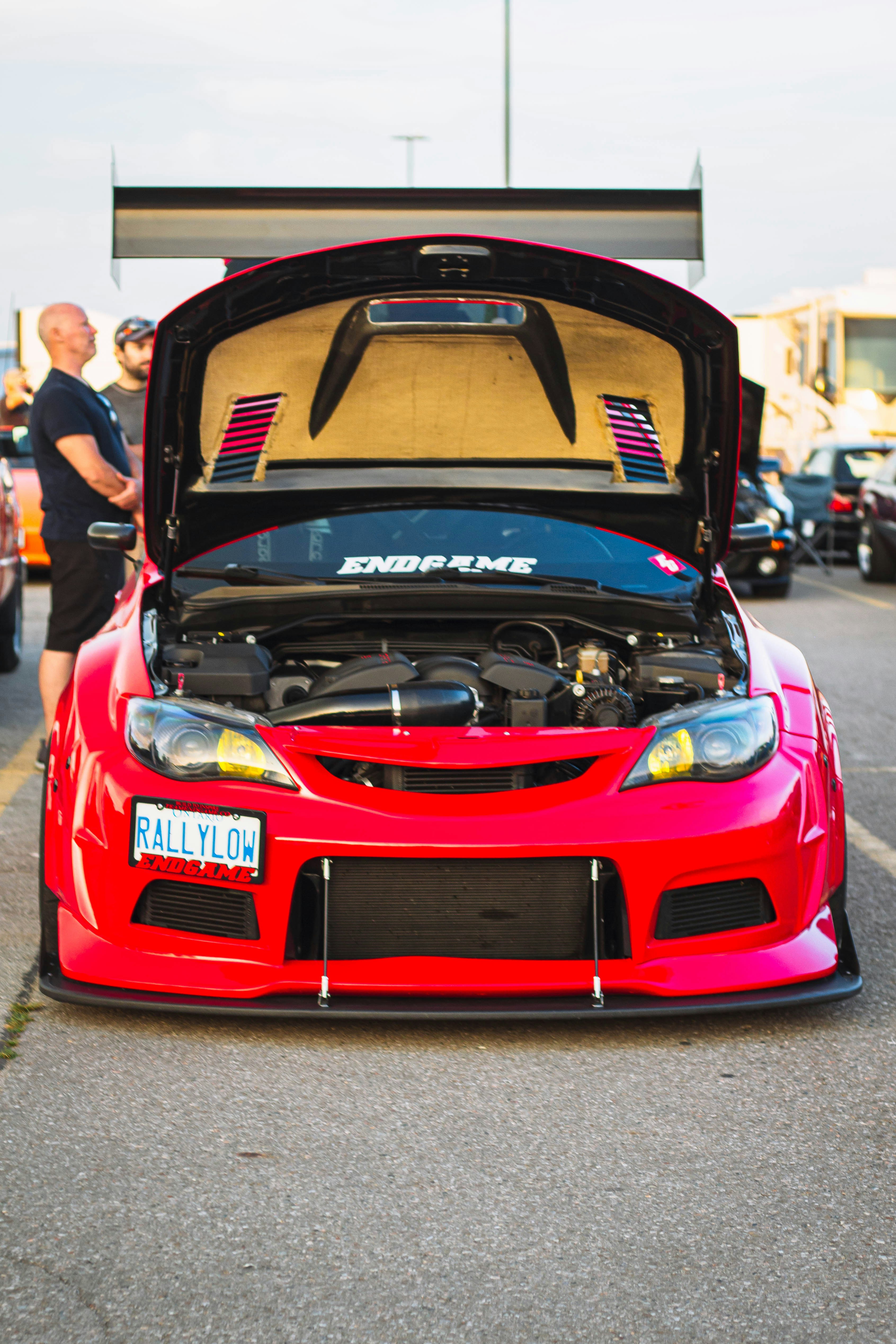 Open-Hood Rally Red: A Front-Facing Car Under Studio Lights