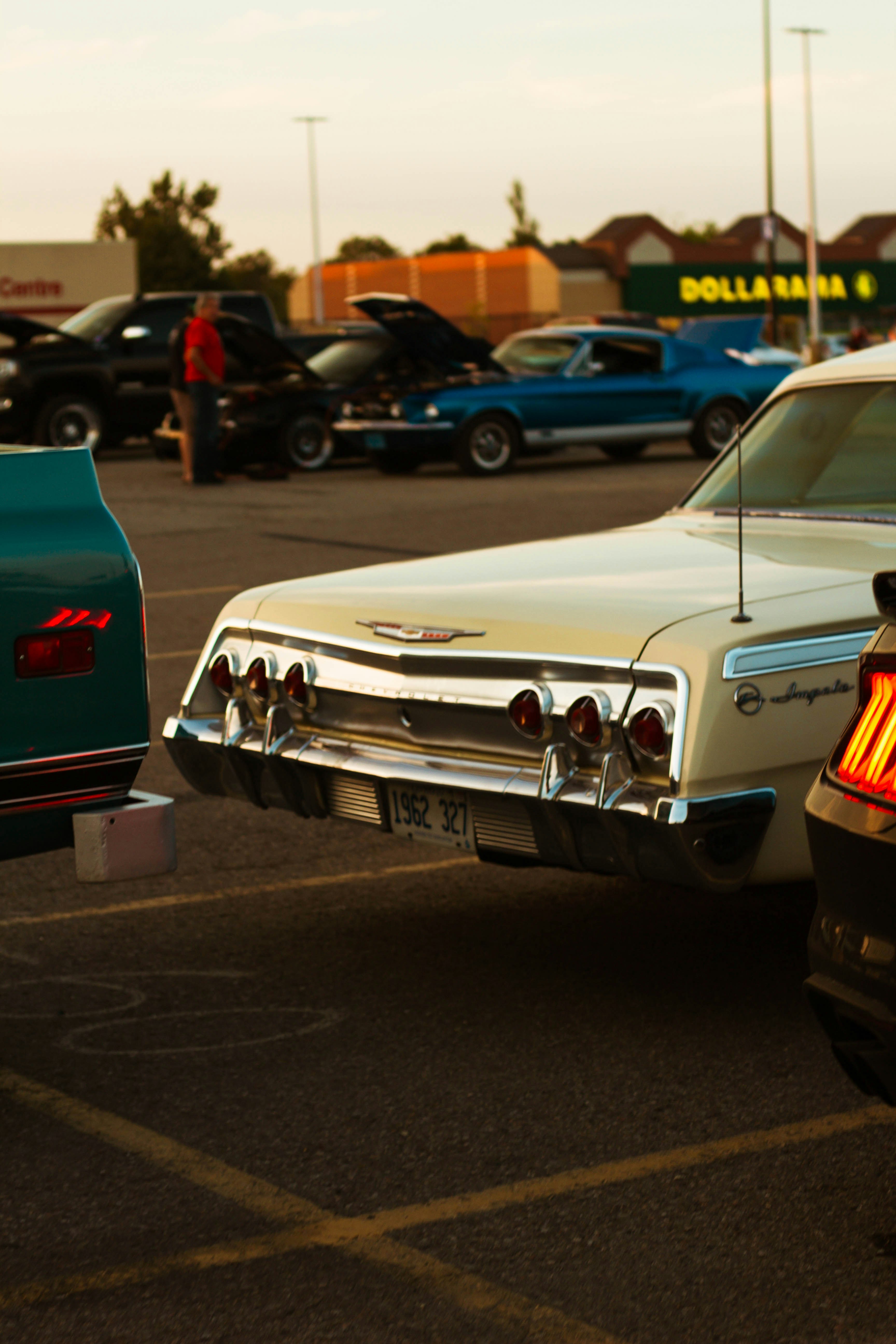 A white vintage Chevrolet Impala parked in a lot during the golden hour