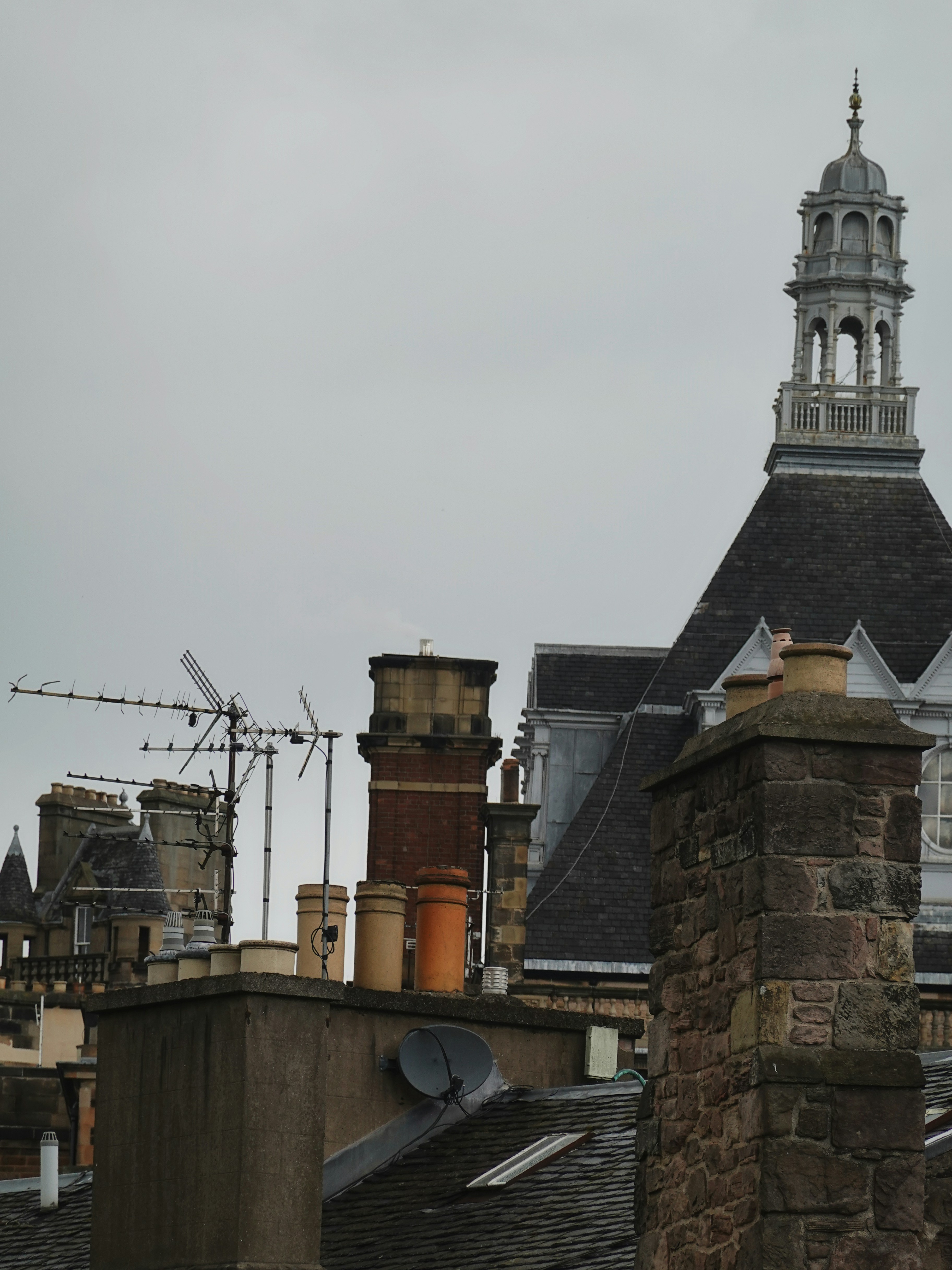 Rooftop Dusk: Slate, Chimneys, and a Stately Bell-tower