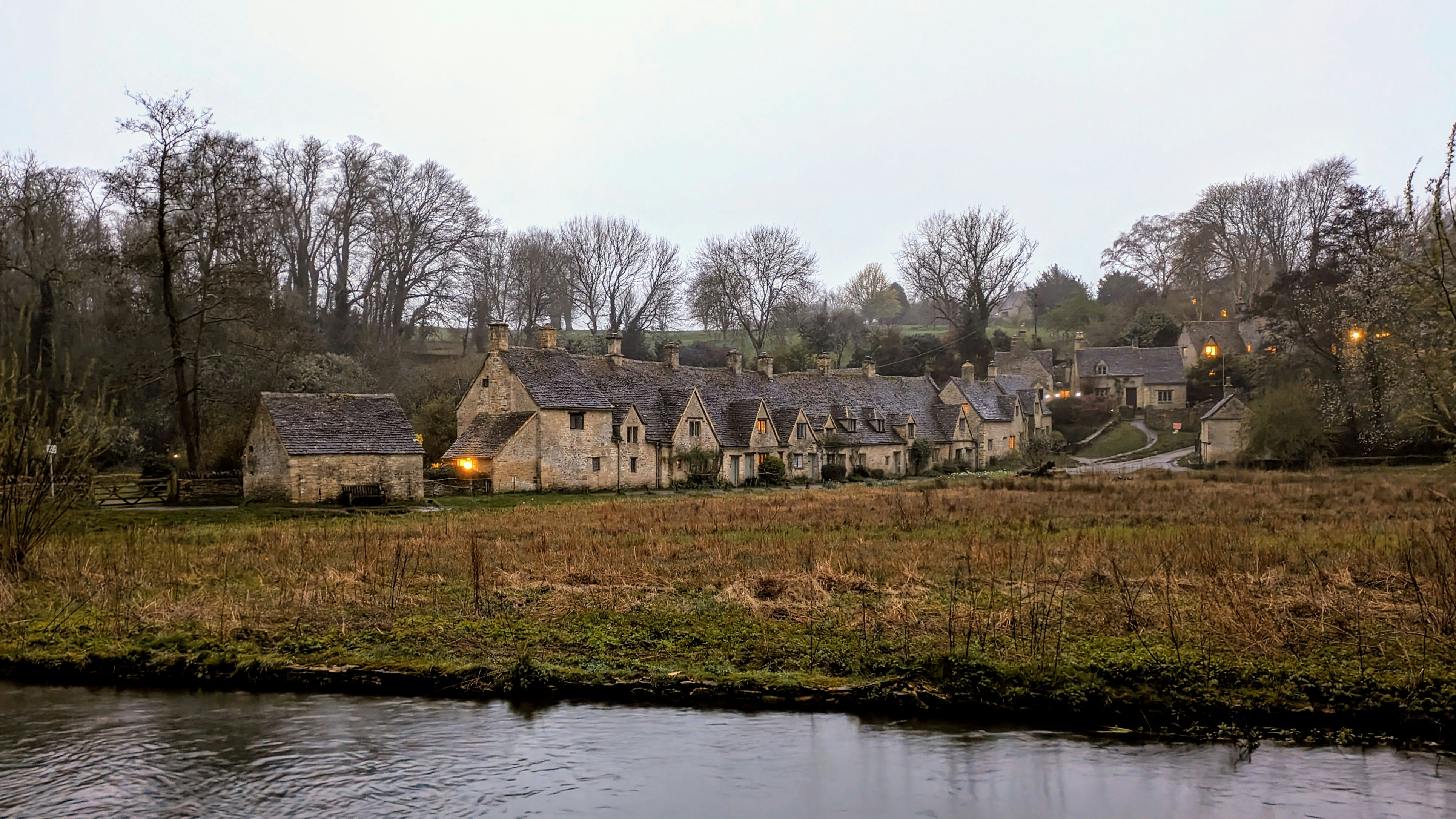 Stone cottages along the riverbank under a muted autumn sky
