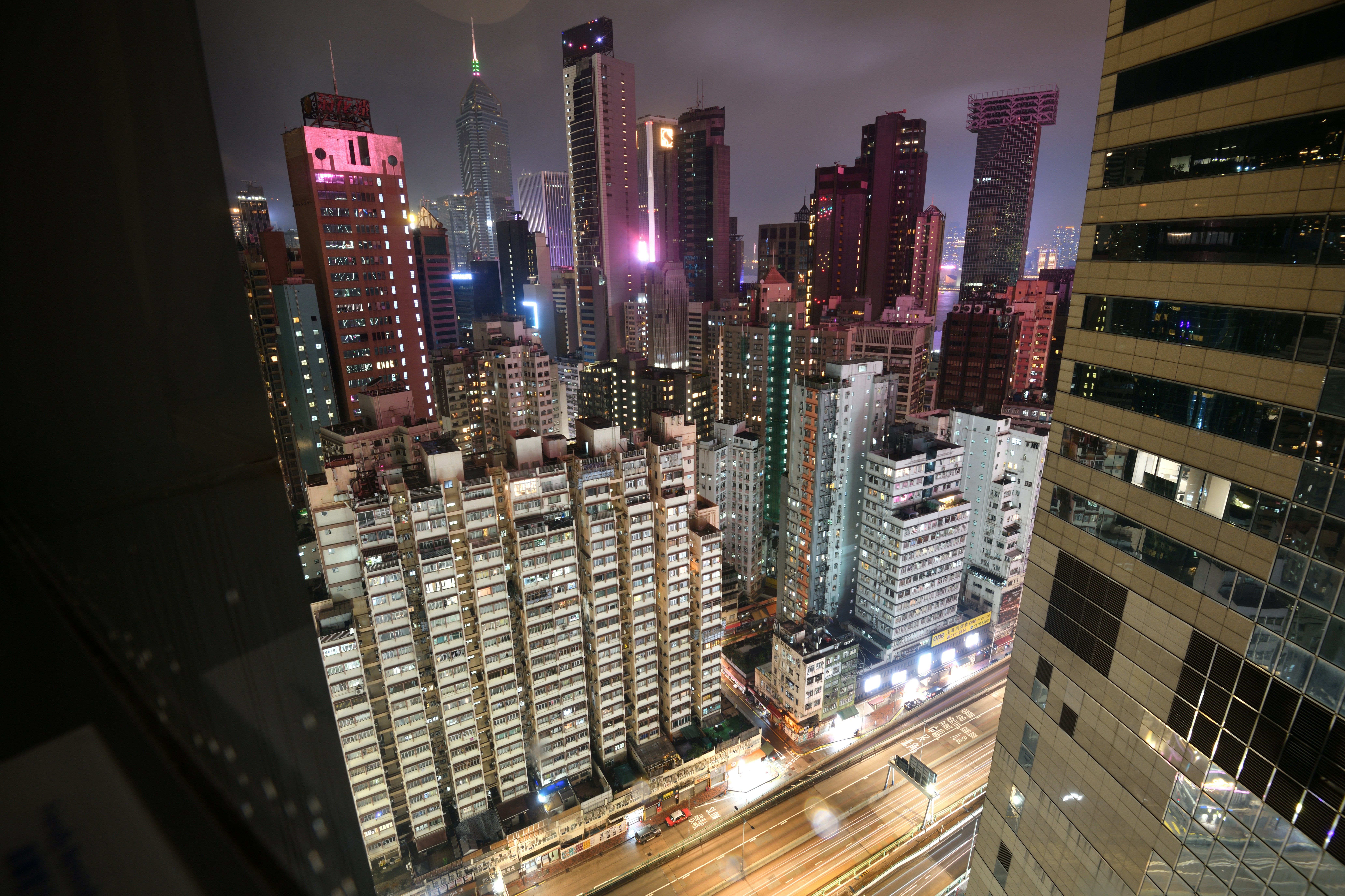 Vertical City Pulse: Neon Towers Over a Bright Main Street
