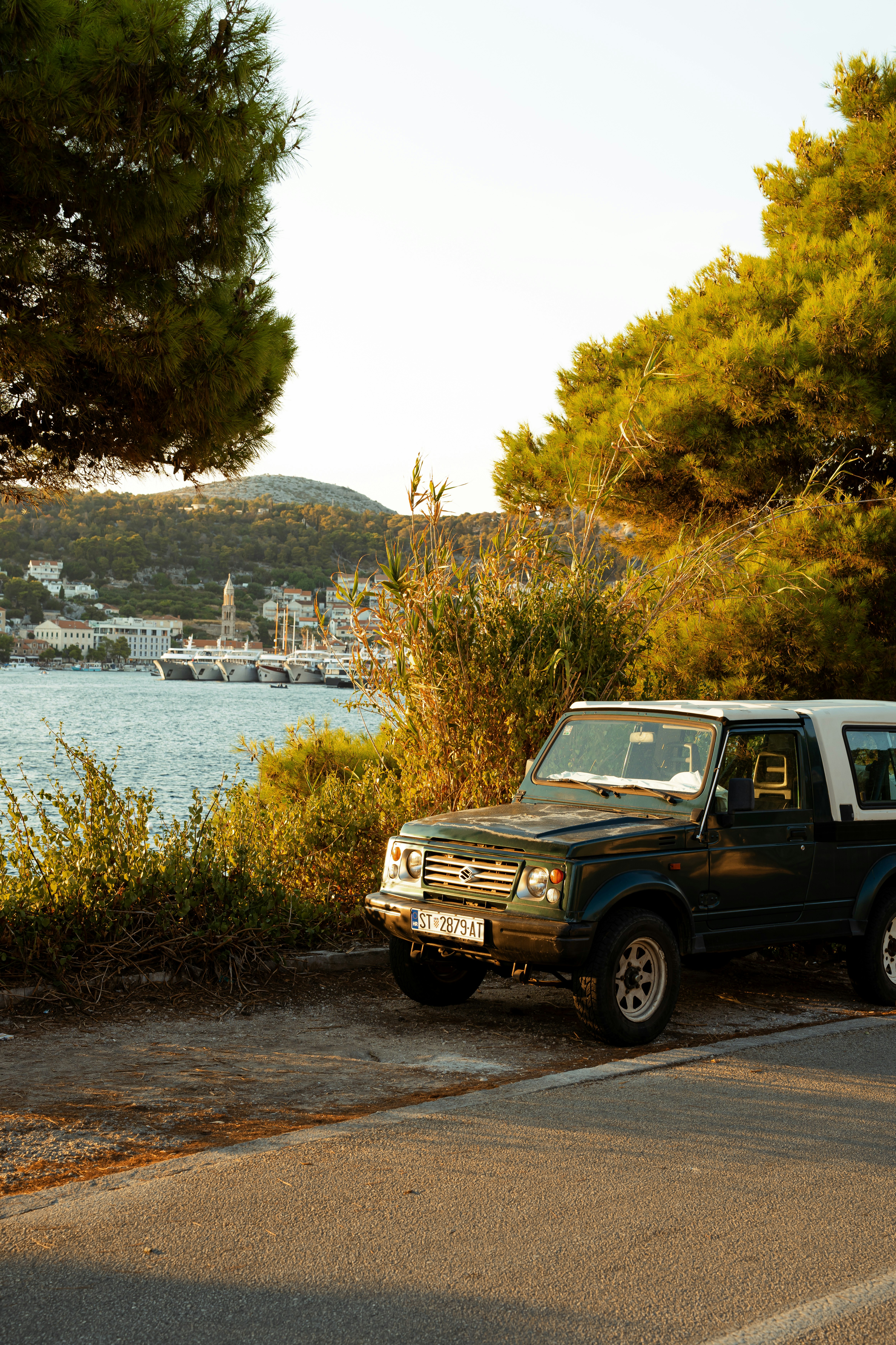 Sunlit Coastal Drive: A Lone SUV by the Quiet Shore