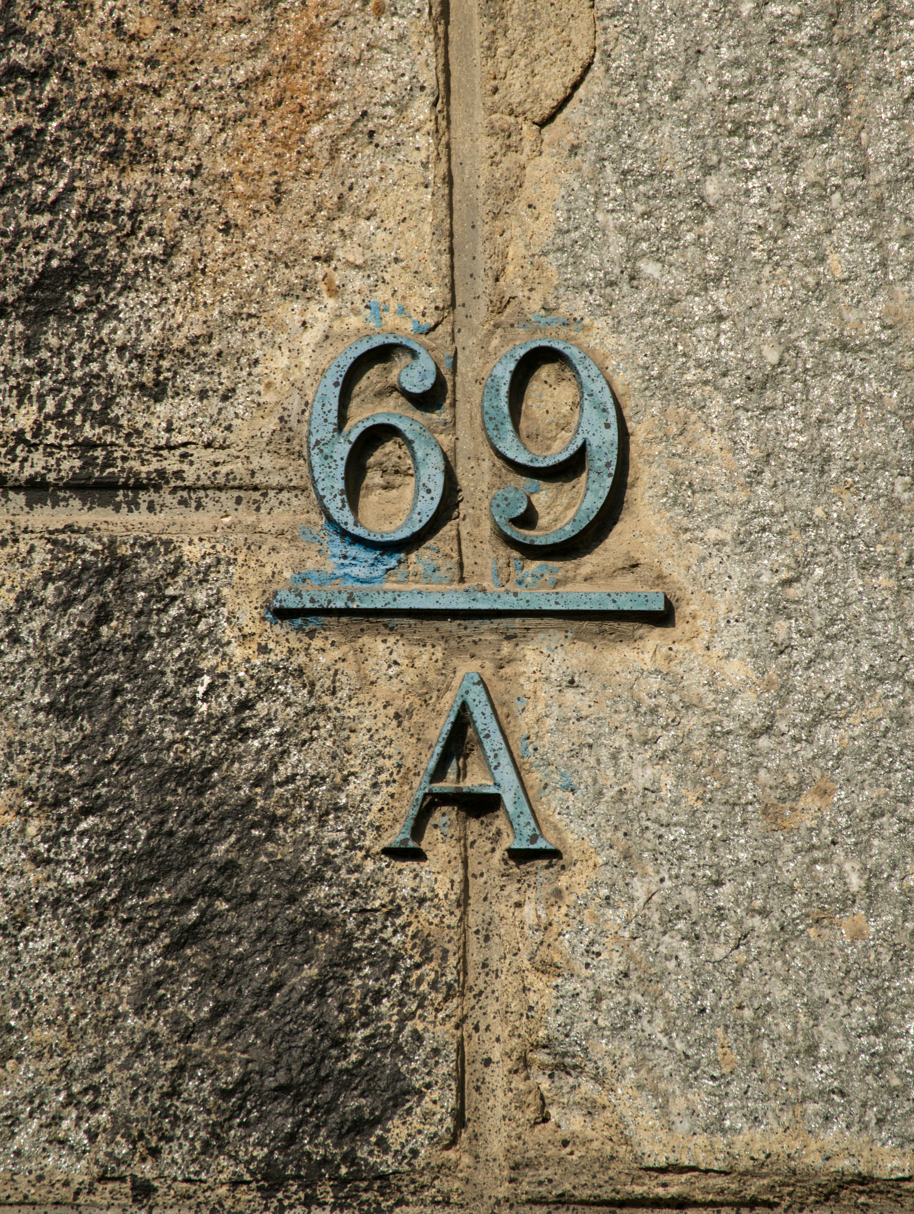 Numbers and Letter: A Weathered Address Mark on Stone