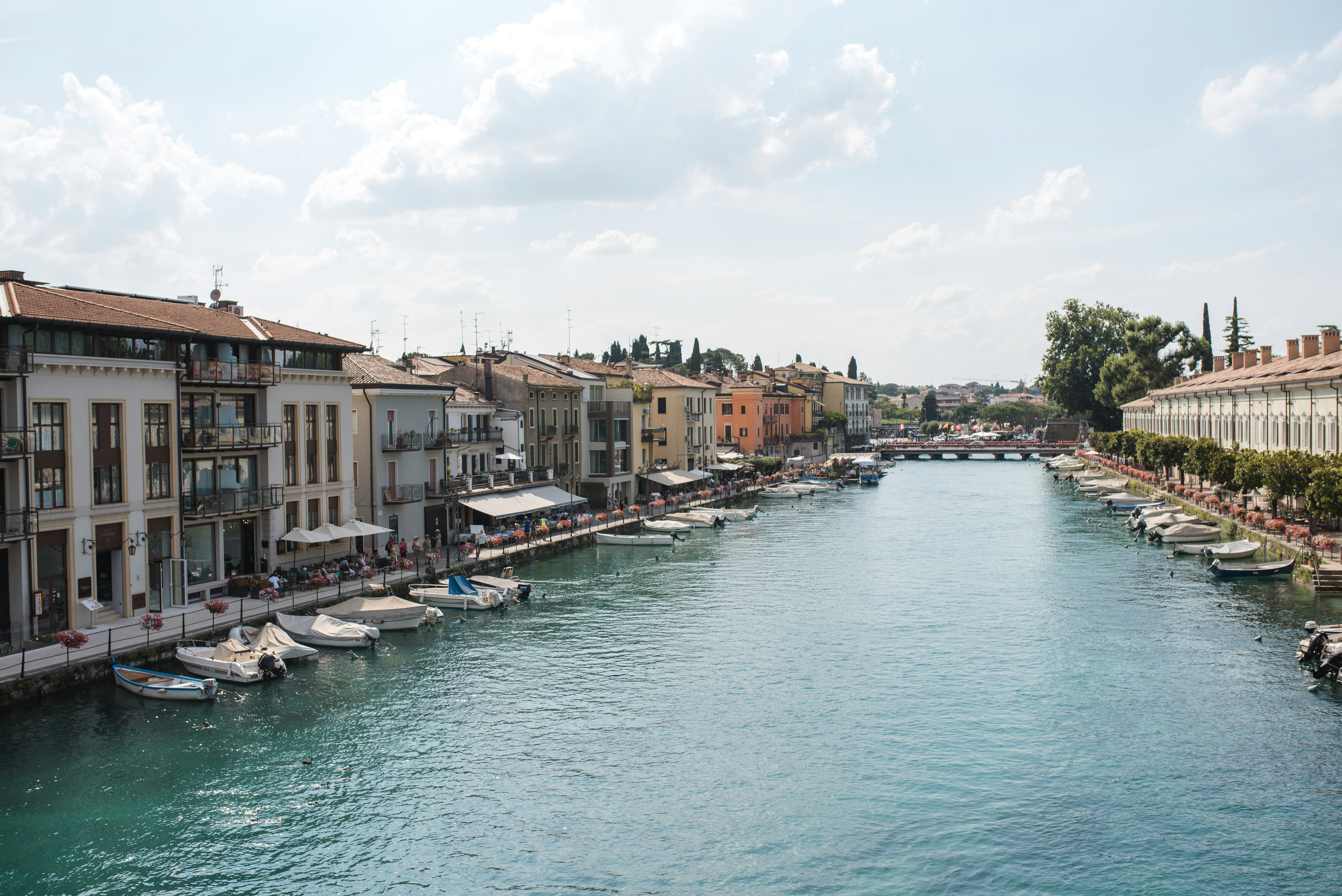 Canalfront Café Row: Boats and pastel facades under a bright summer sky