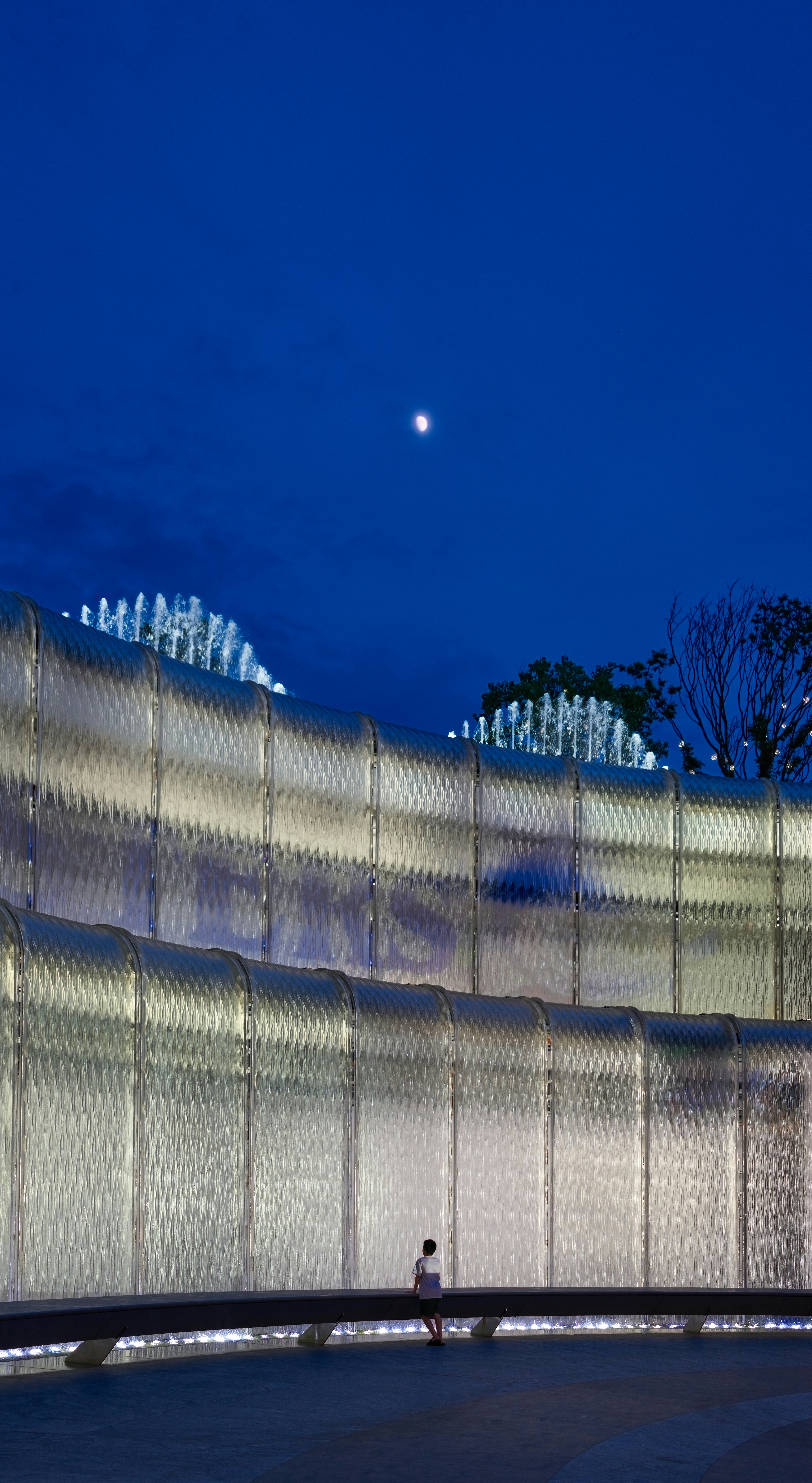 Moonlit Glass: A lone figure walks the edge of a luminous metallic wall