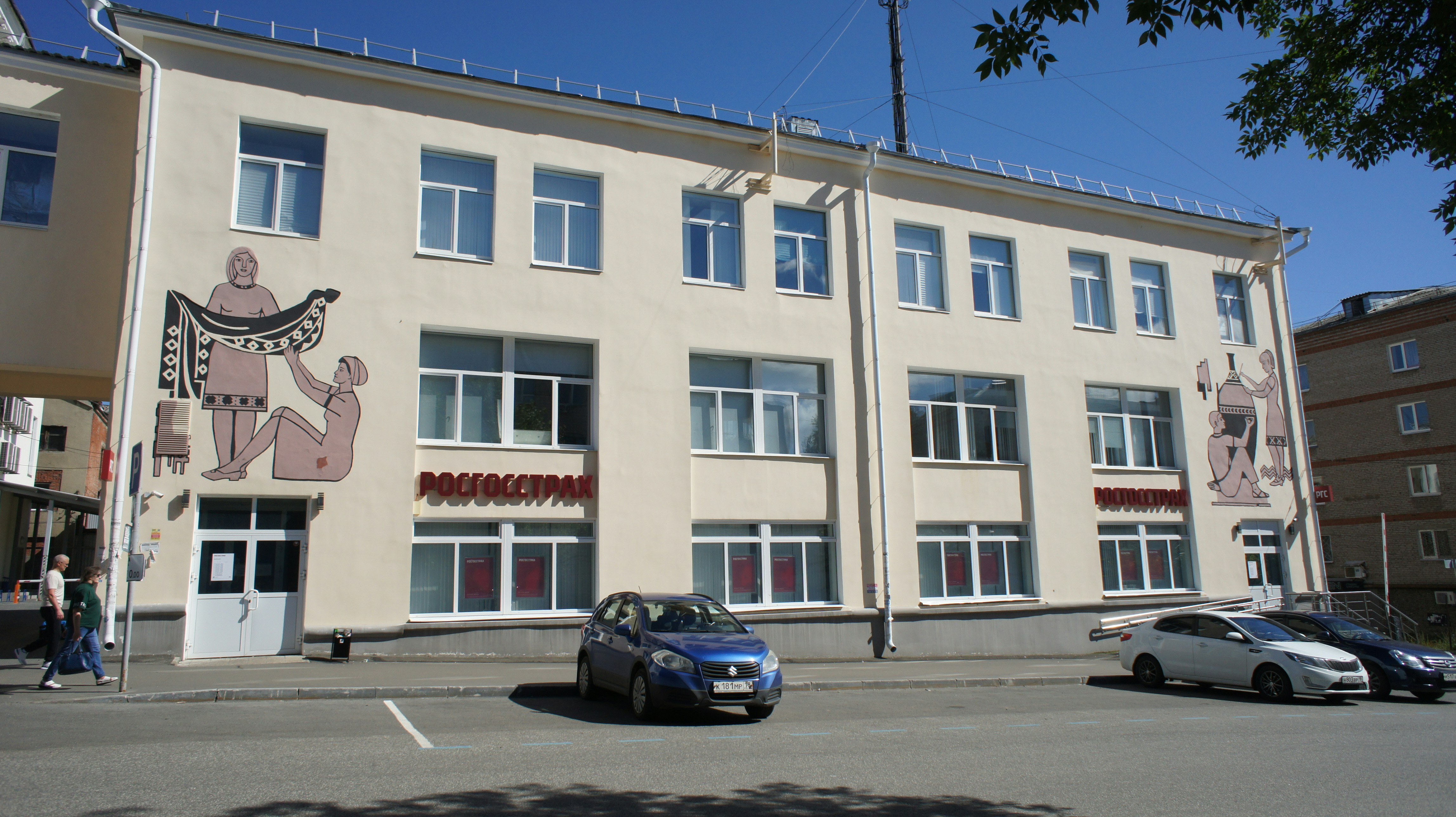 Facade of a municipal building adorned with murals and arched entrance