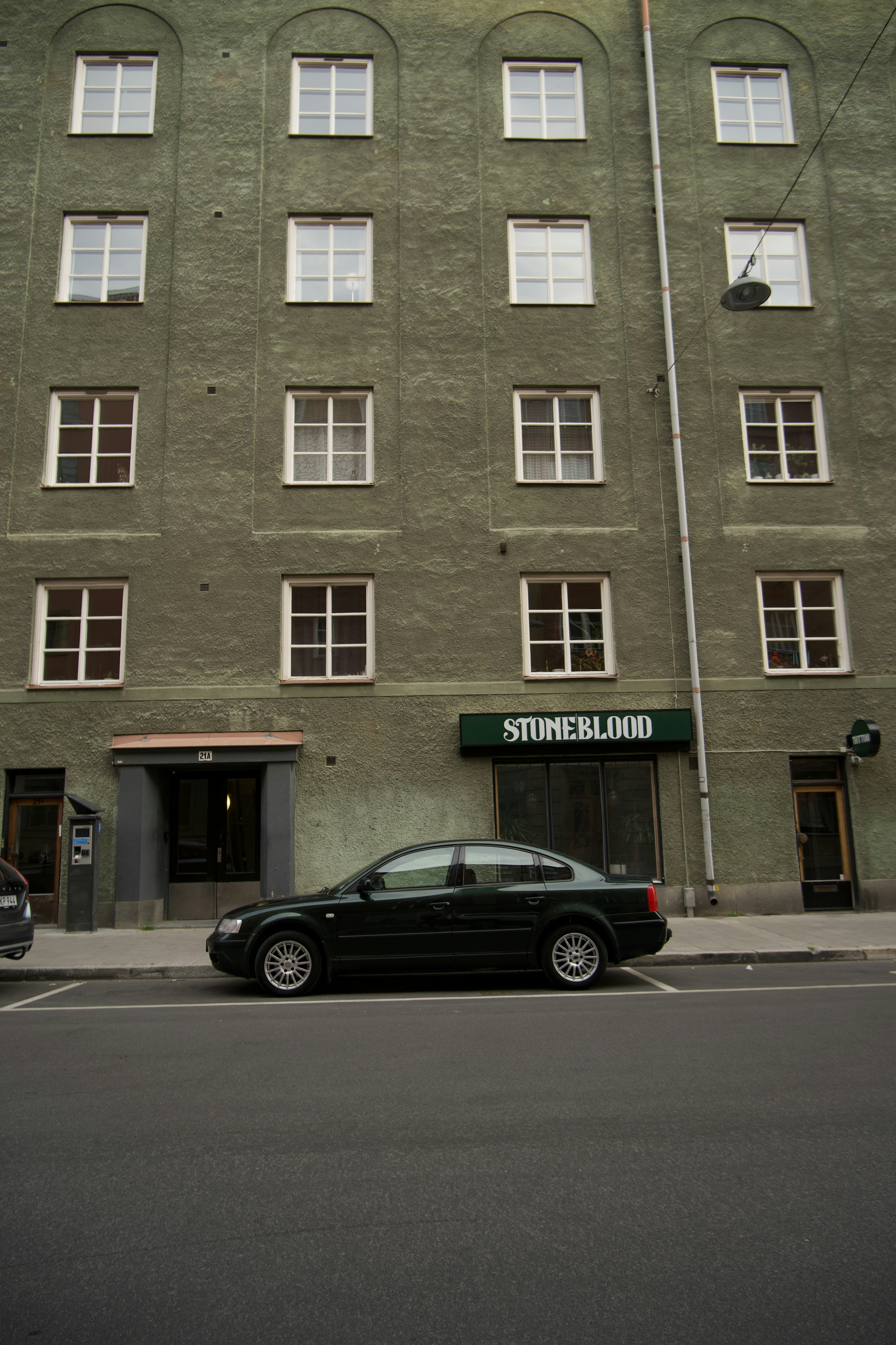 Green Facade, Car, and a Sign that Reads Stoneblood