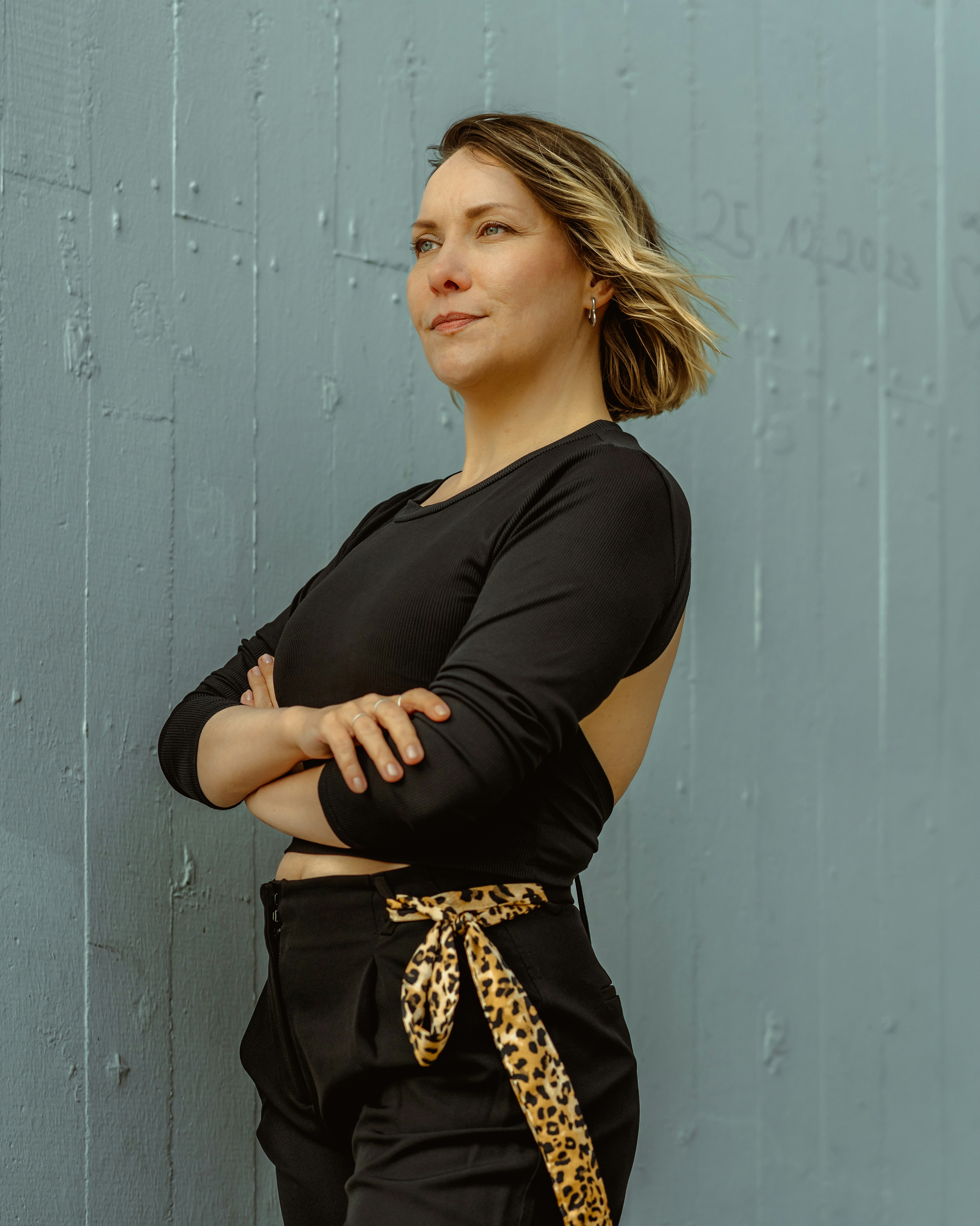 Crossed Arms, Confident Gaze Against a Weathered Wall