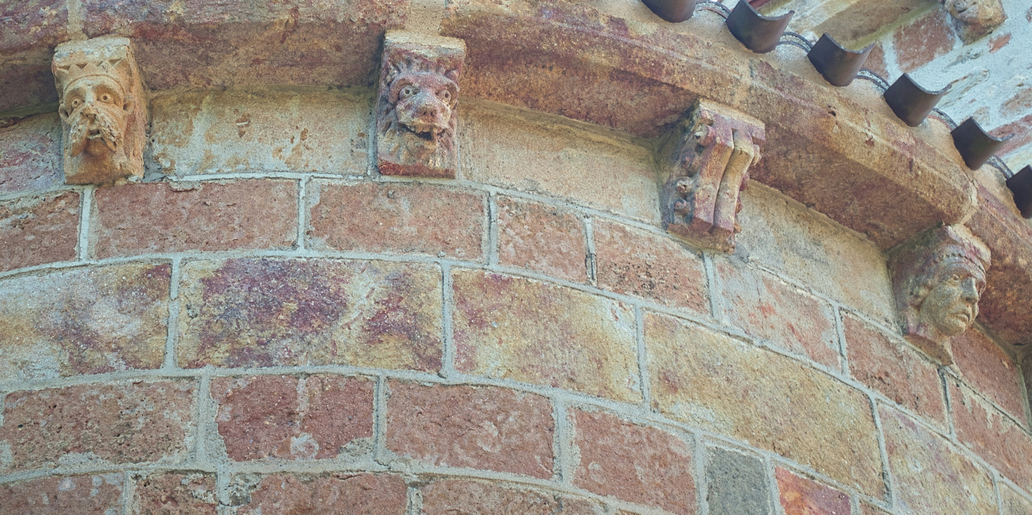 Carved stone faces guard a brick arch