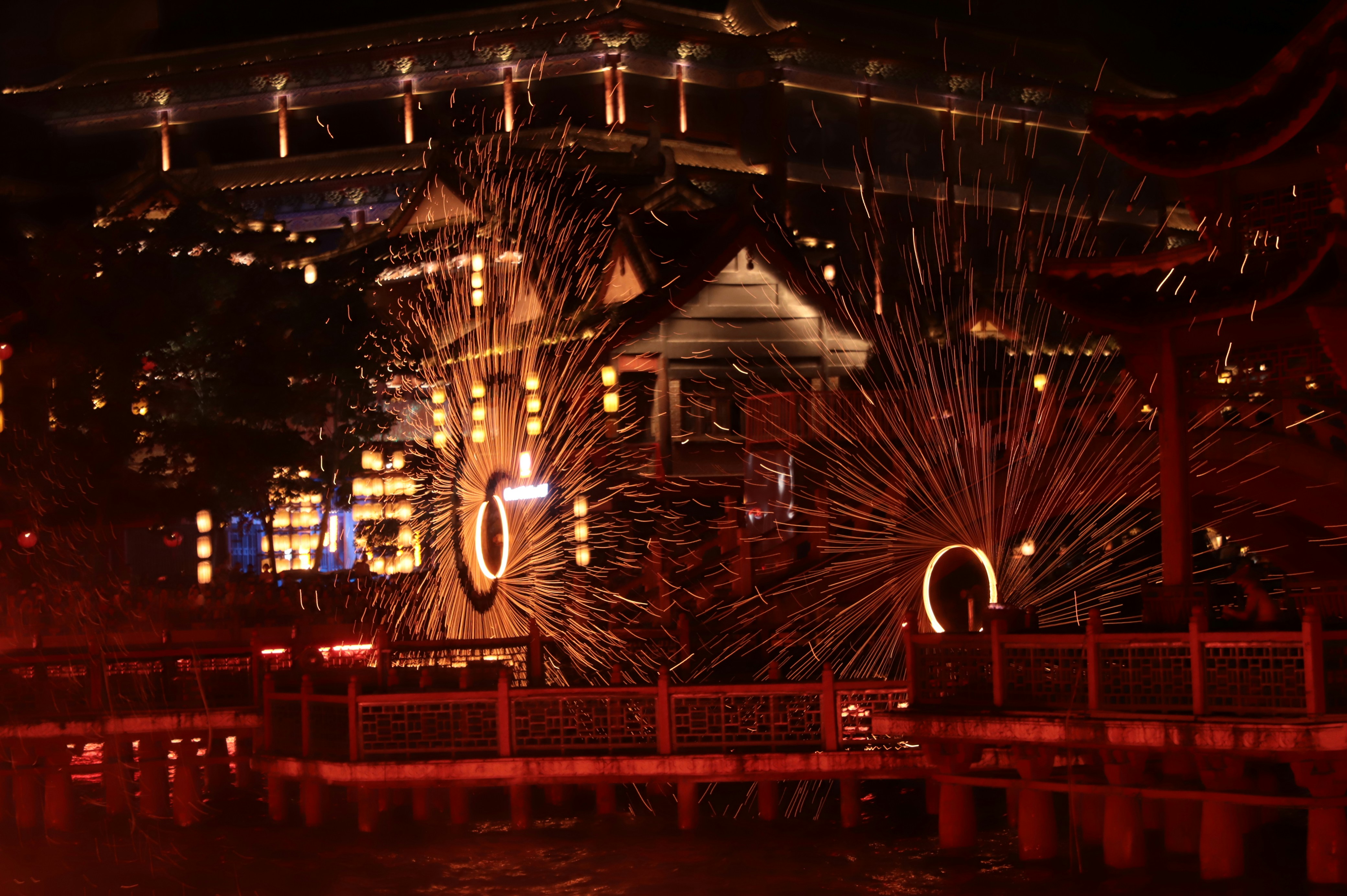 Fireworks Behind a Lantern-Lit Pier: Nighttime Reflections Over Calm Water