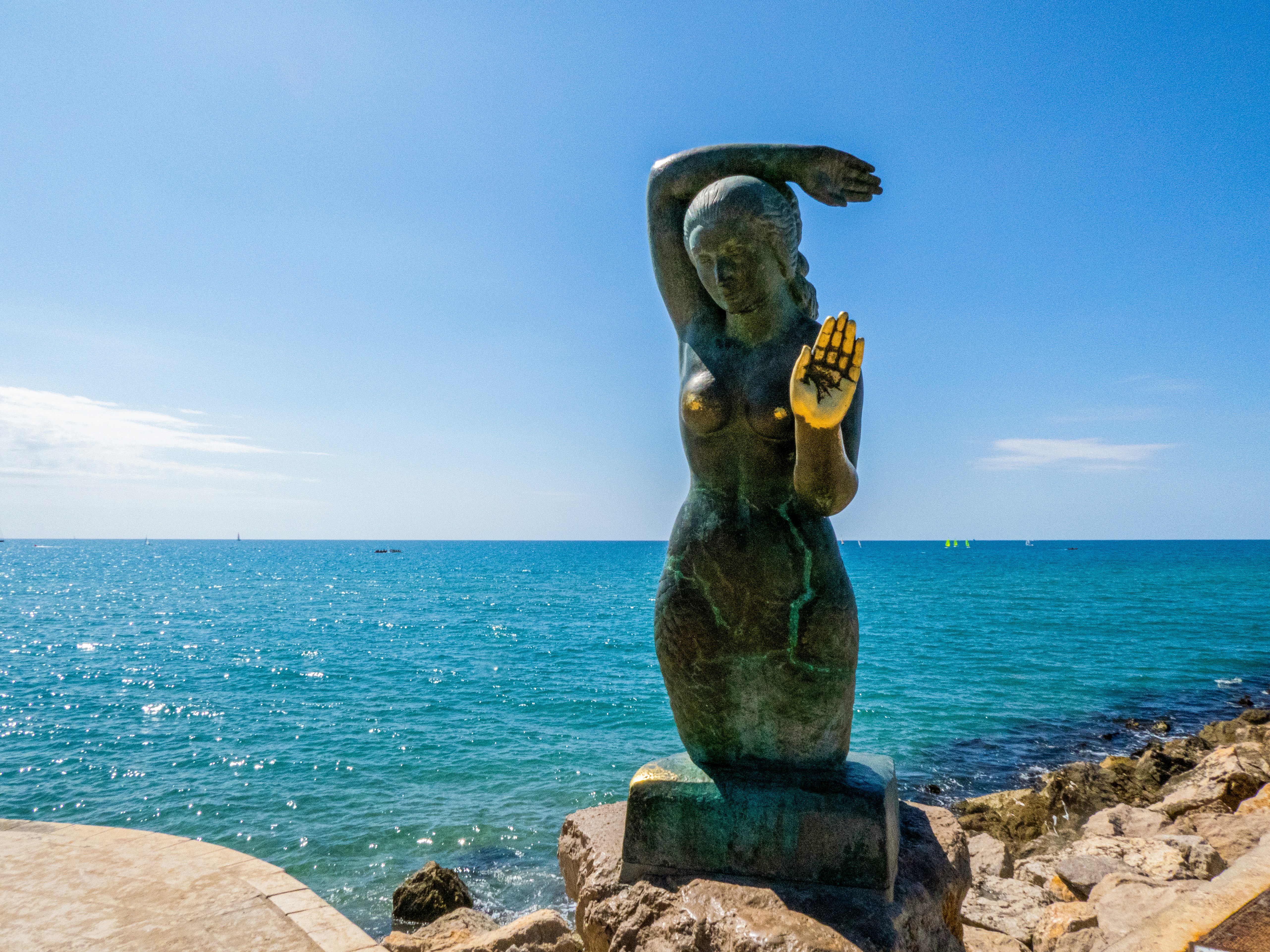 Sea-Sculpted Sentinel: a statue watches the horizon by rocky shore