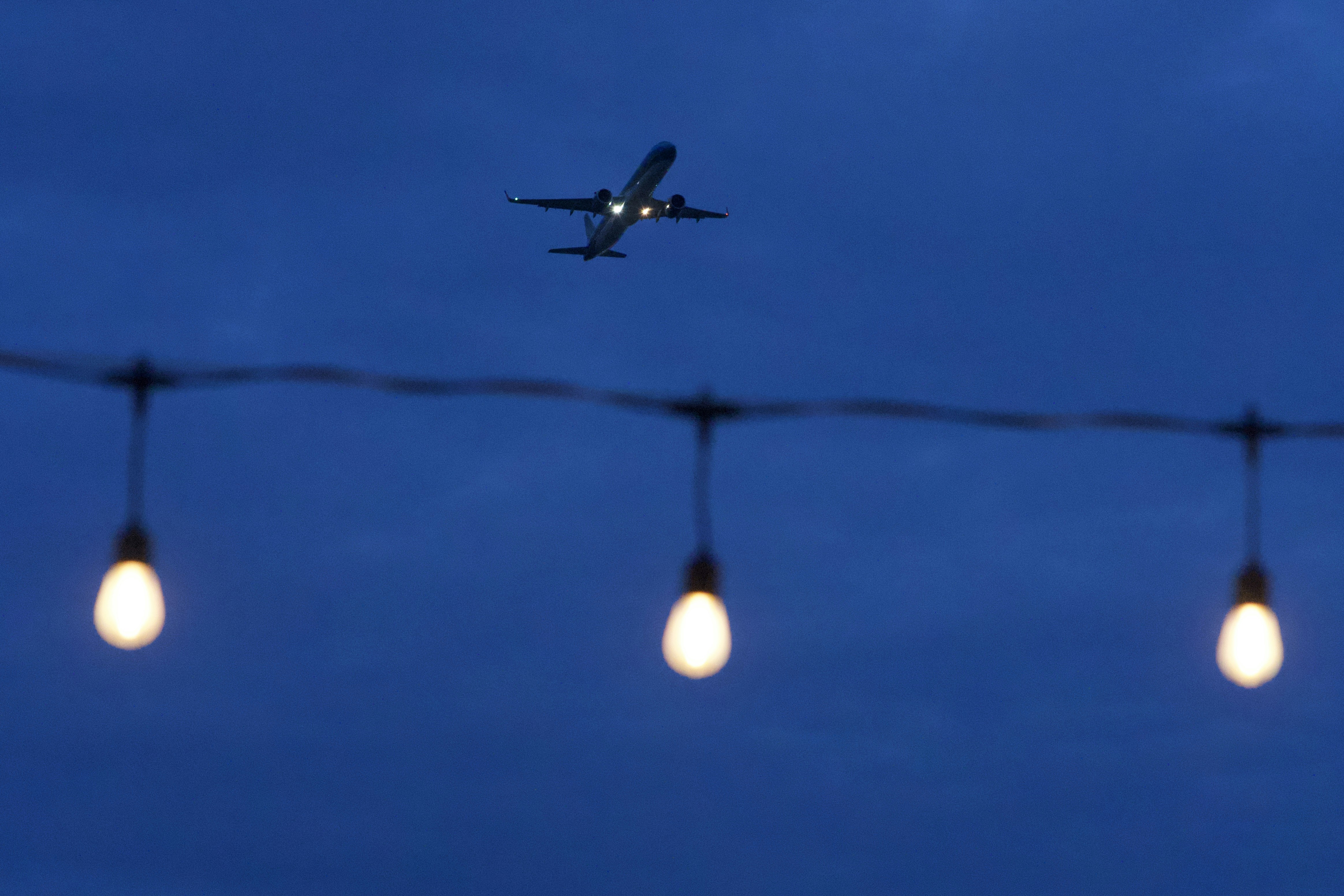 A nocturnal approach: airplane silhouettes above a string of glowing bulbs