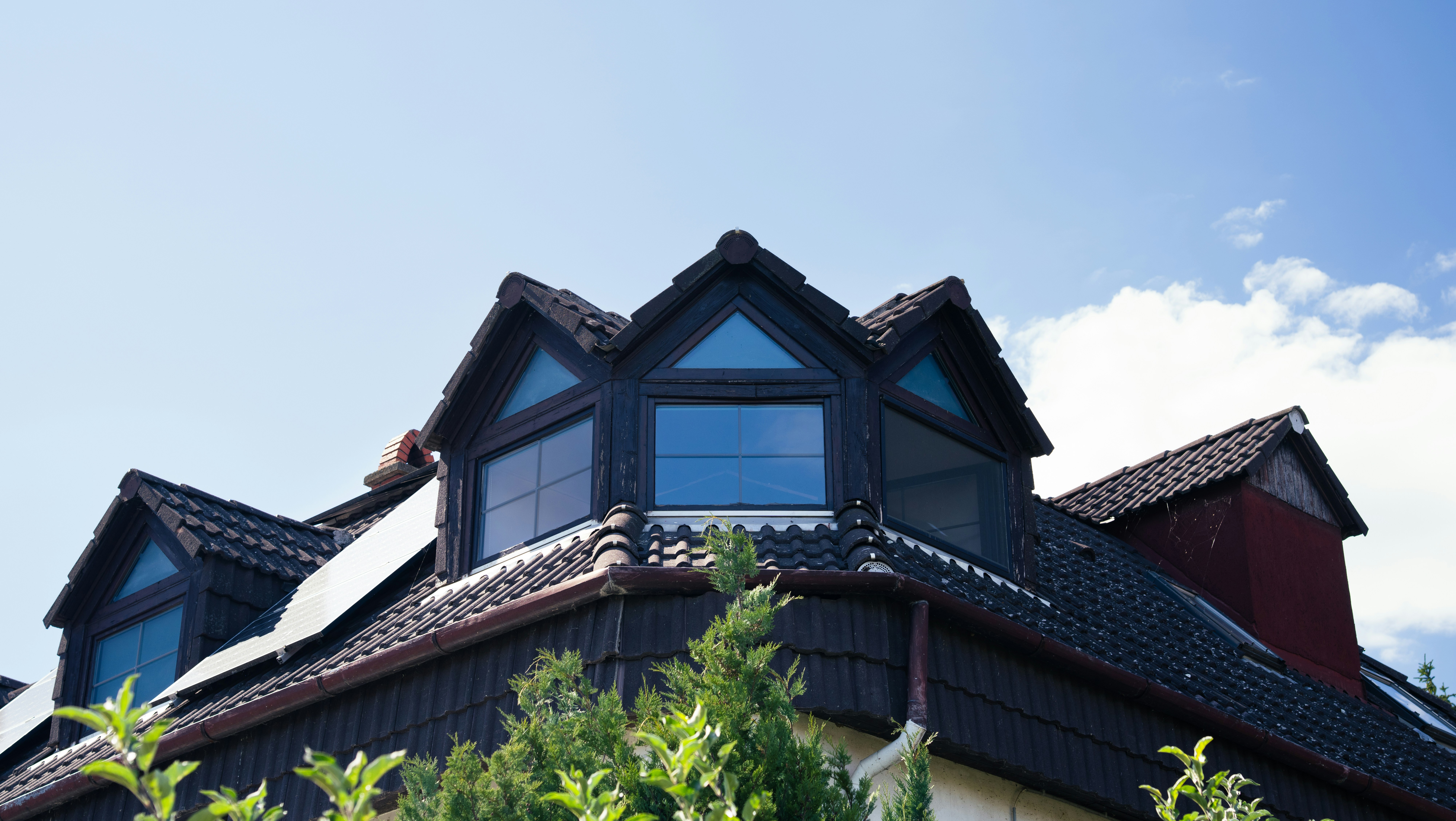 Dormer Window Portrait: A Triad of Gables against a Bright Sky