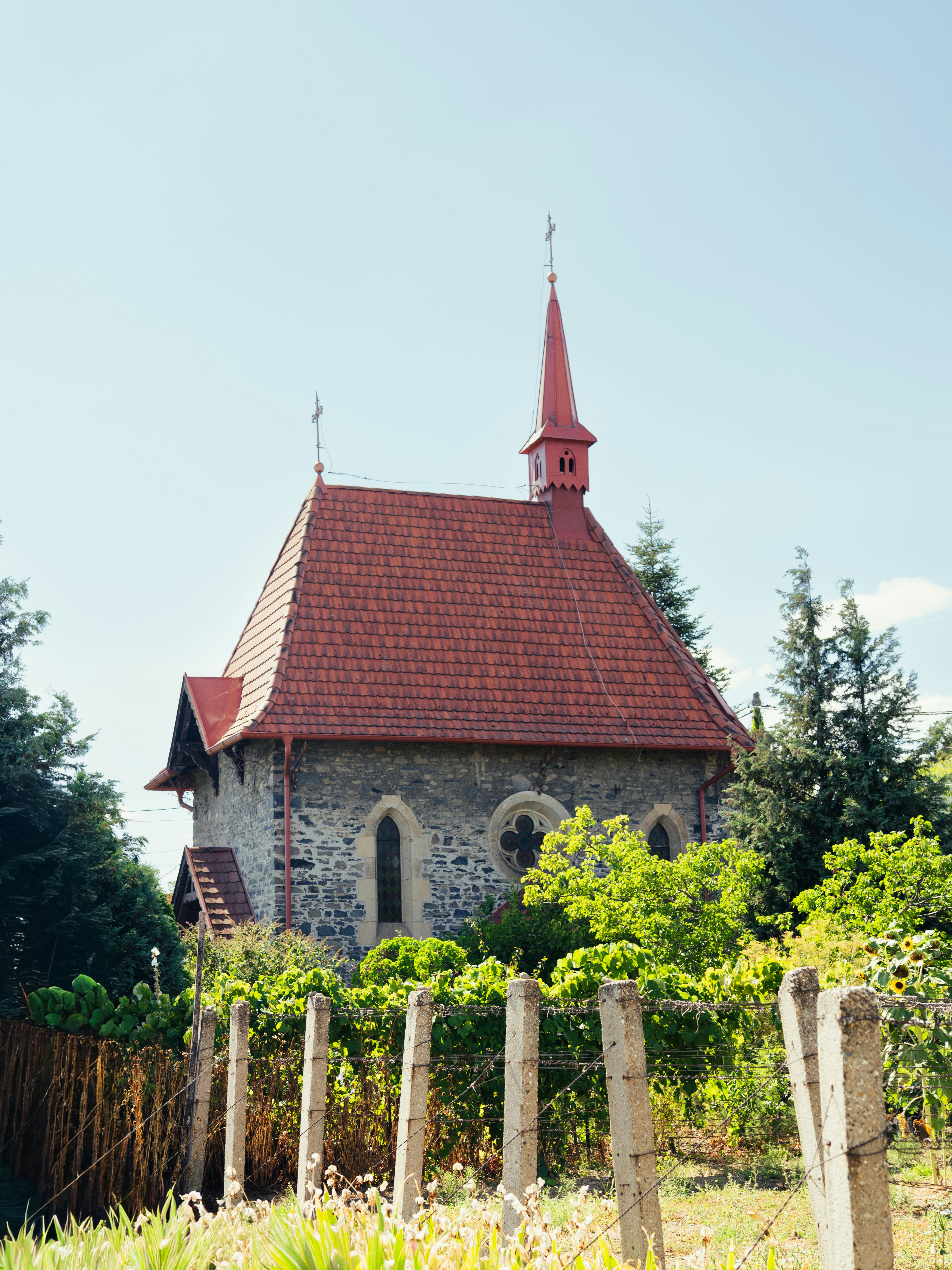 Red Roofed Chapel Rising Above a Greened Fence