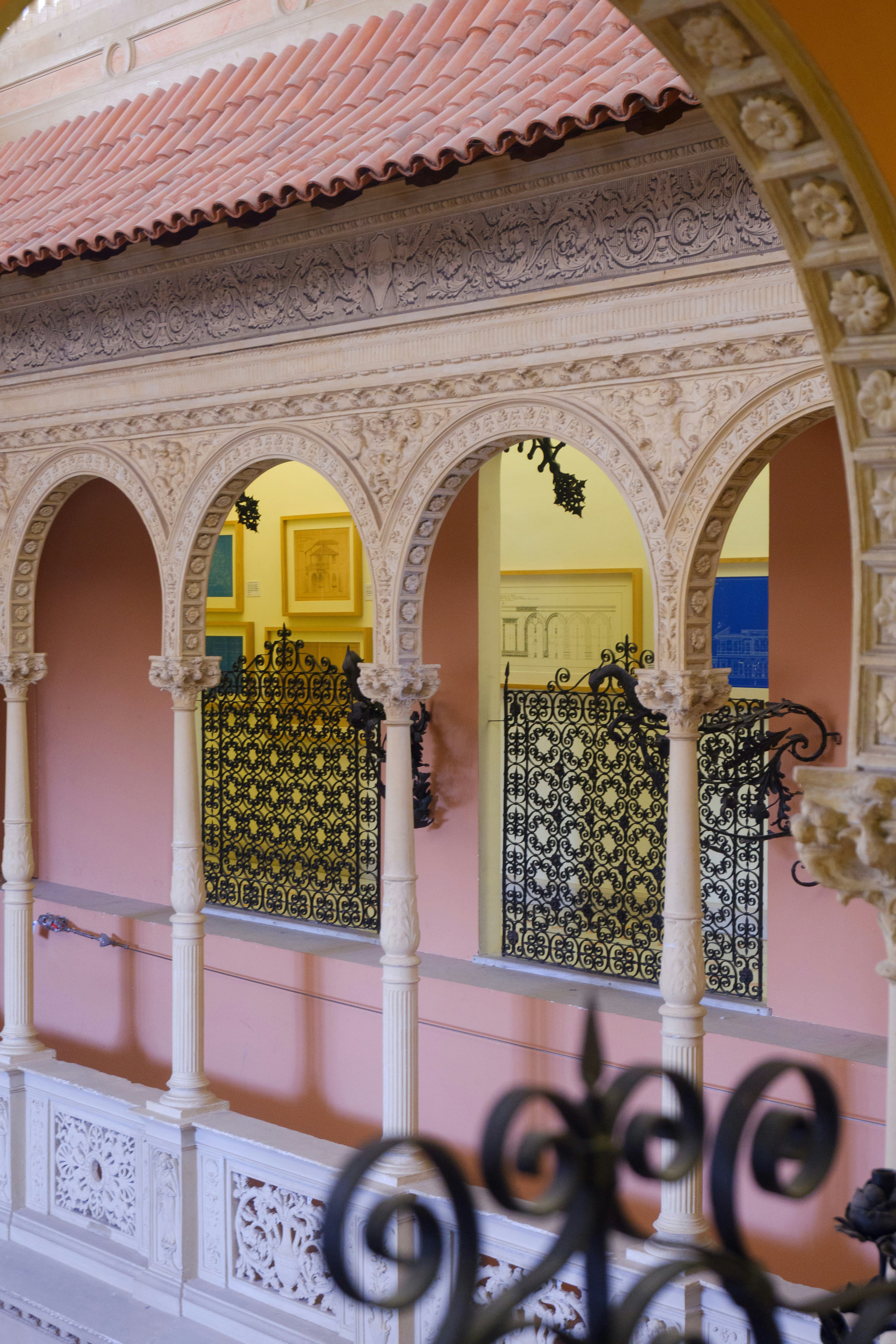 Ornate arches and ironwork through a sunlit courtyard