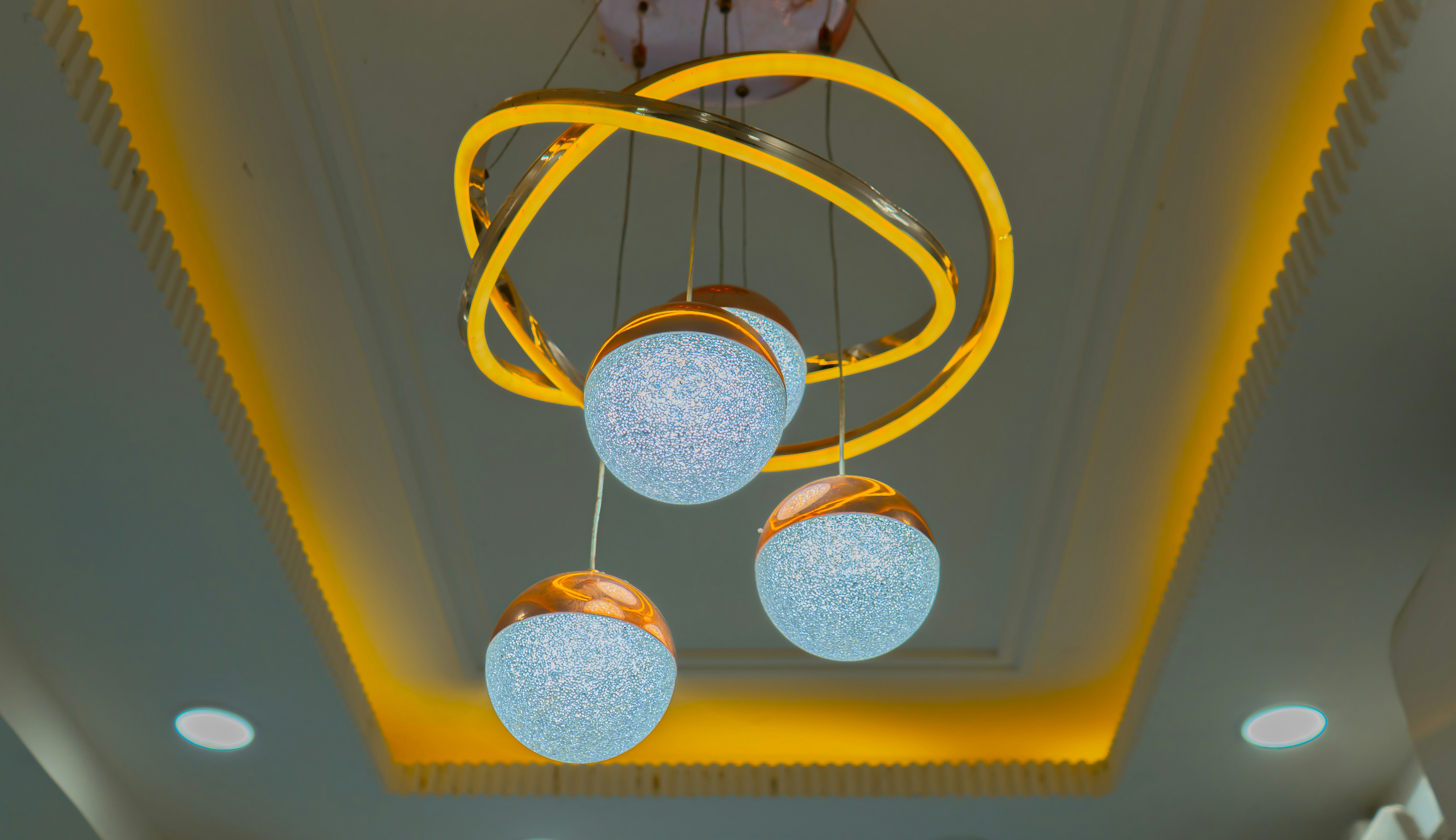 Orbital Glow: Modern Pendant Lights Hover over a Geometric Ceiling