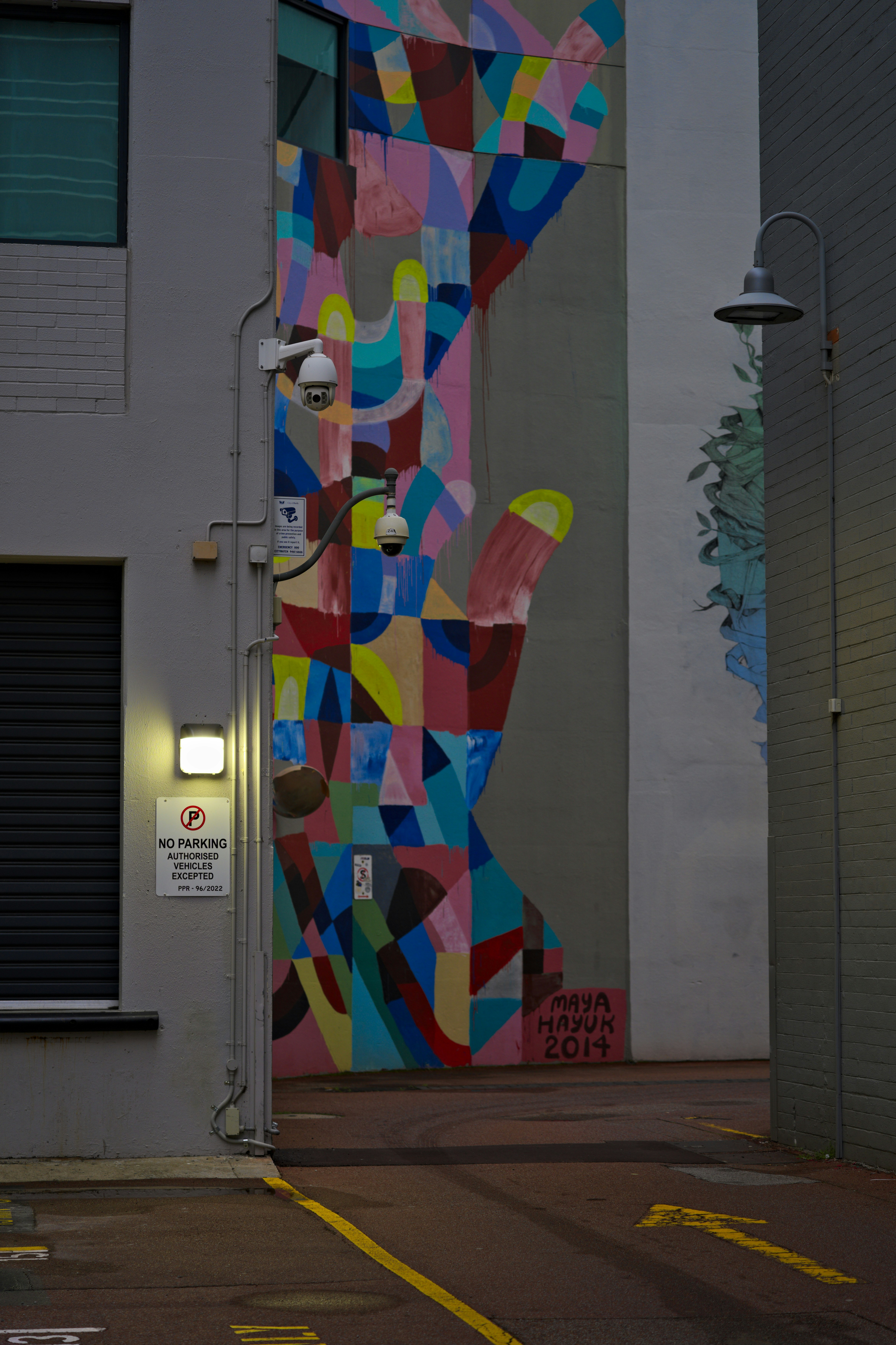 Vivid mural alleyway: color blocks rise along a dim urban corridor