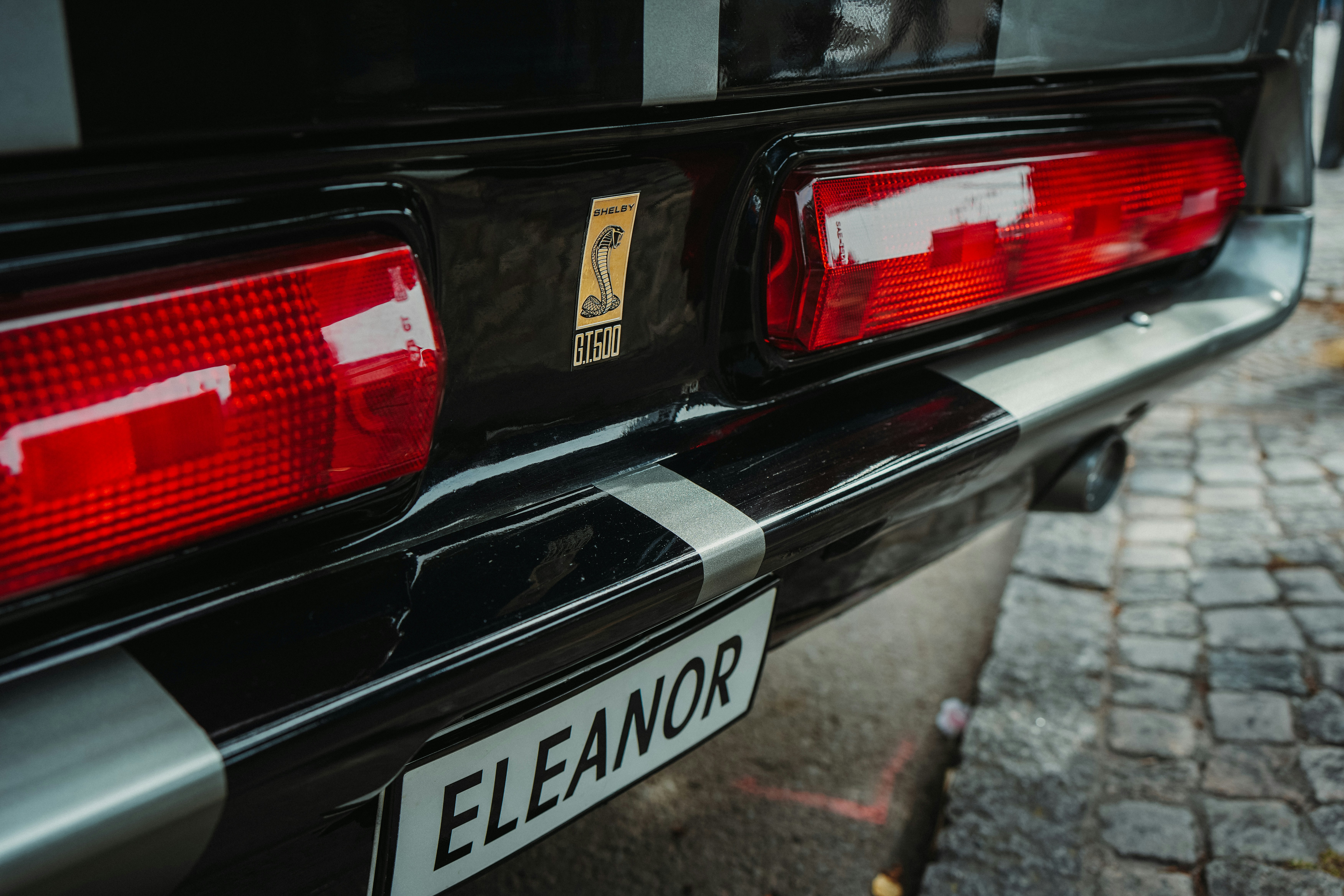 Rear view of a black Shelby GT500 with silver stripes and an Eleanor license plate