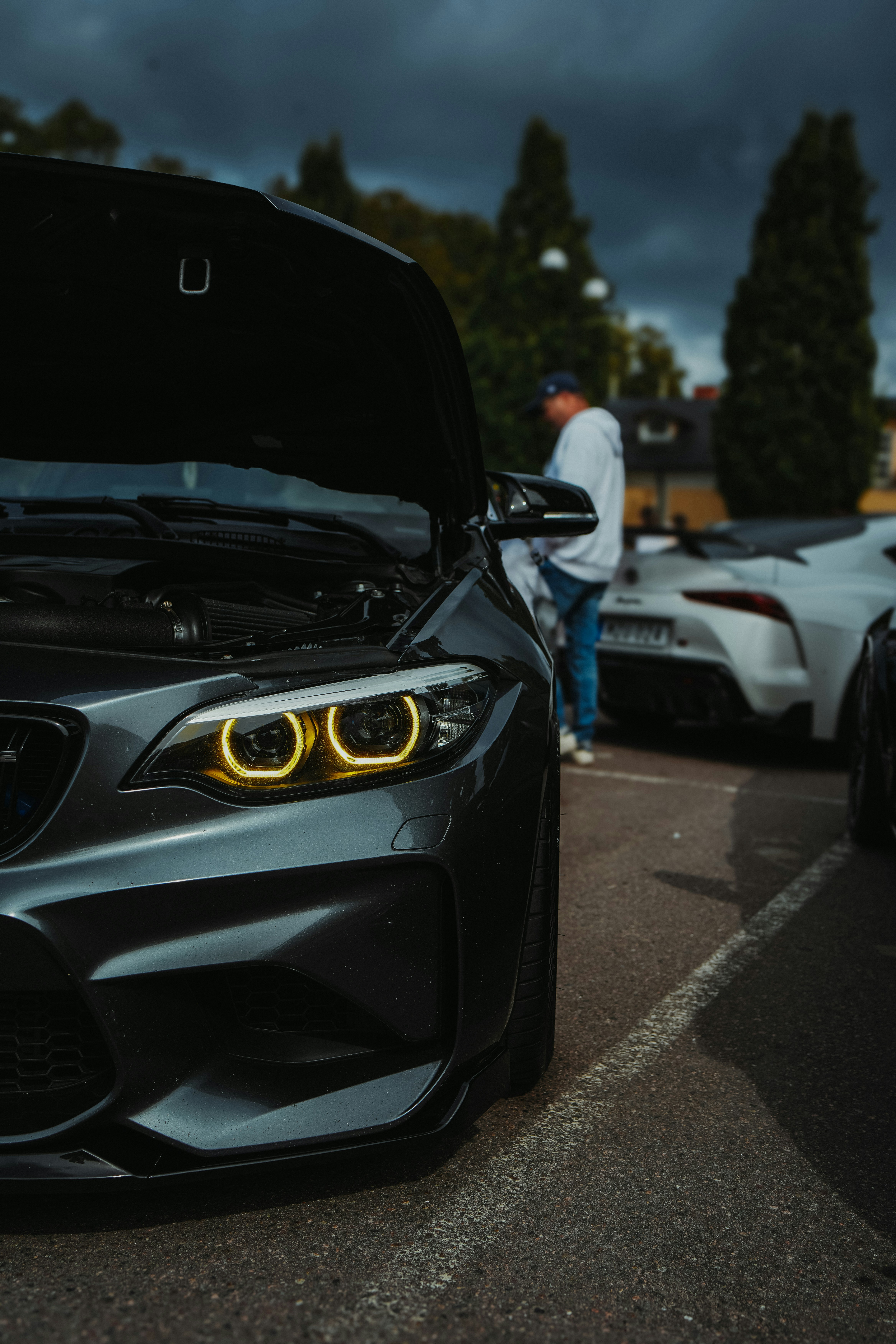 Close-up of a high-performance car headlight with open hood in a parking lot