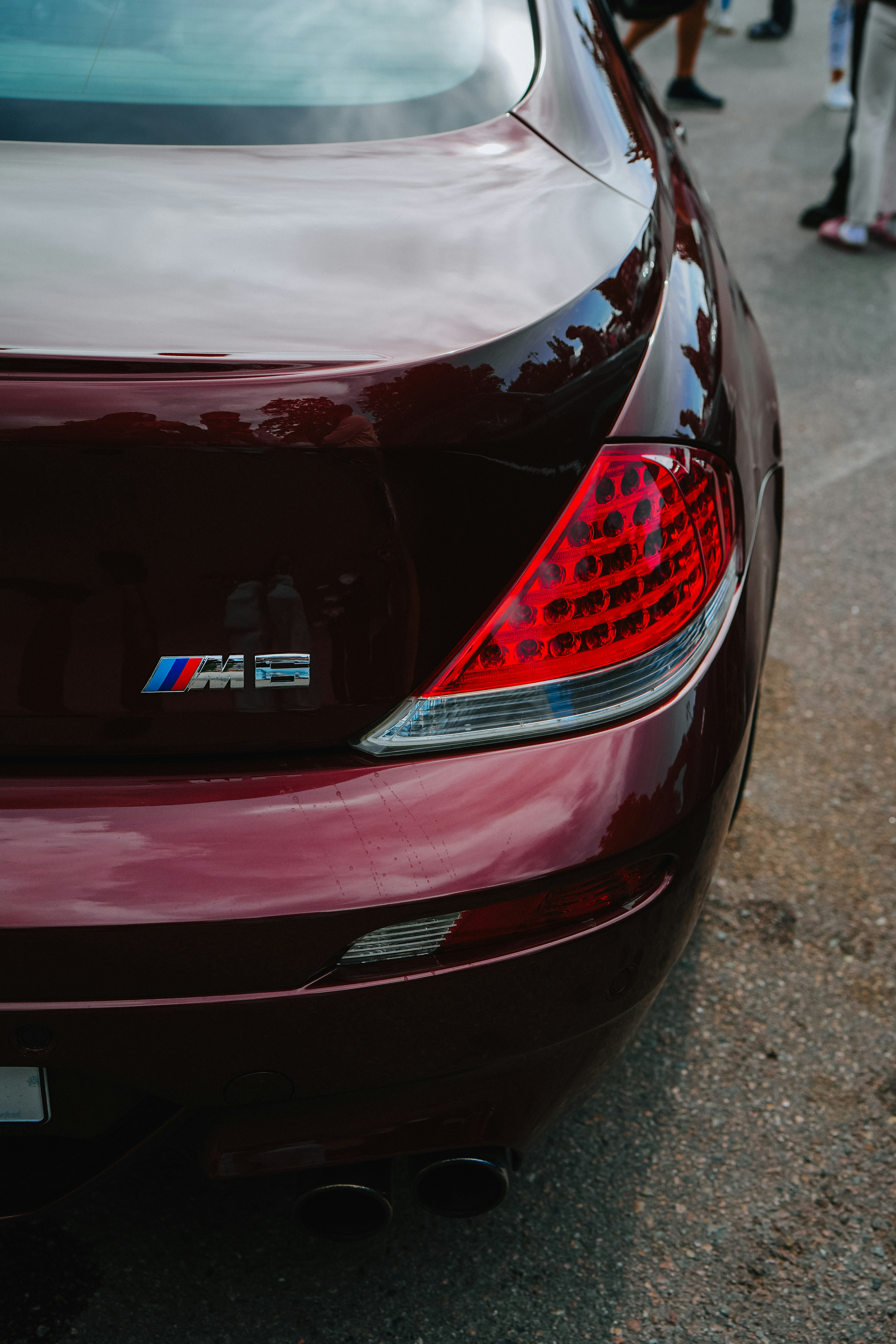 Rear View of a Burgundy BMW M5 Badge: Reflective Surface and Taillight Details