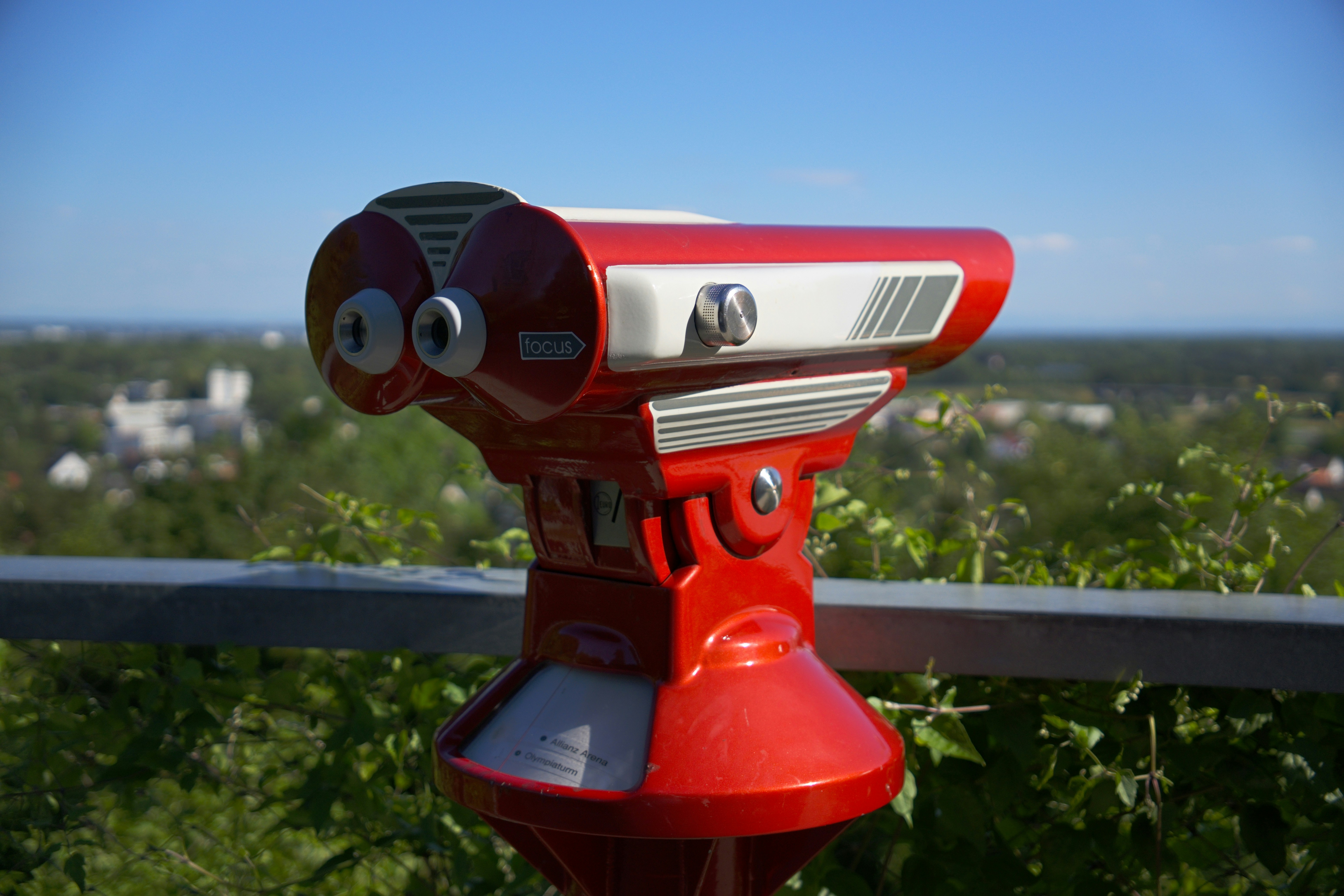 Red telescope portrait: a kiosk viewer overlooking a green valley