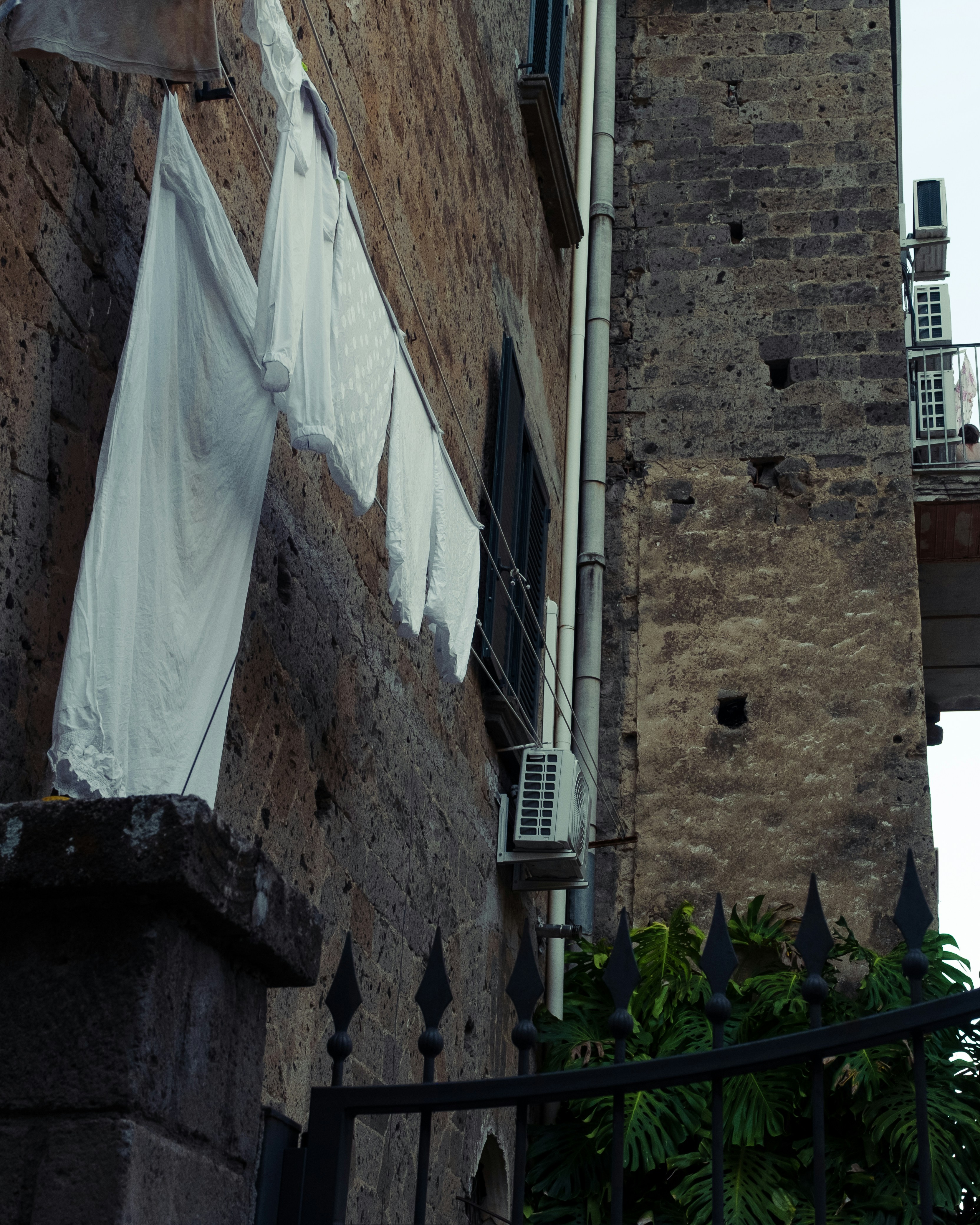 White laundry hanging on a line against a rustic stone building wall