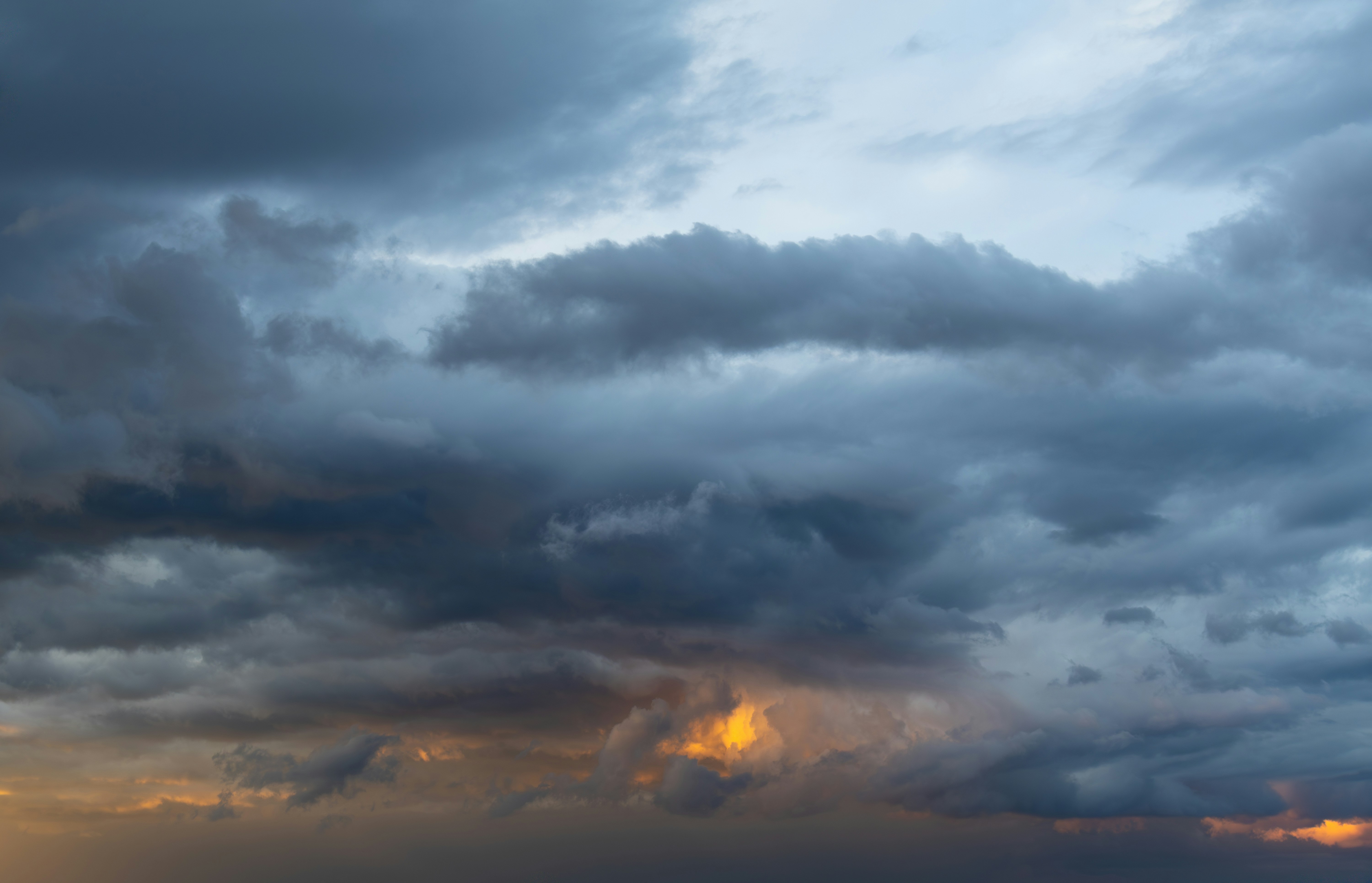 Golden light punctures the cloud layer near the horizon, creating a warm glow against cool blue-gray tones.