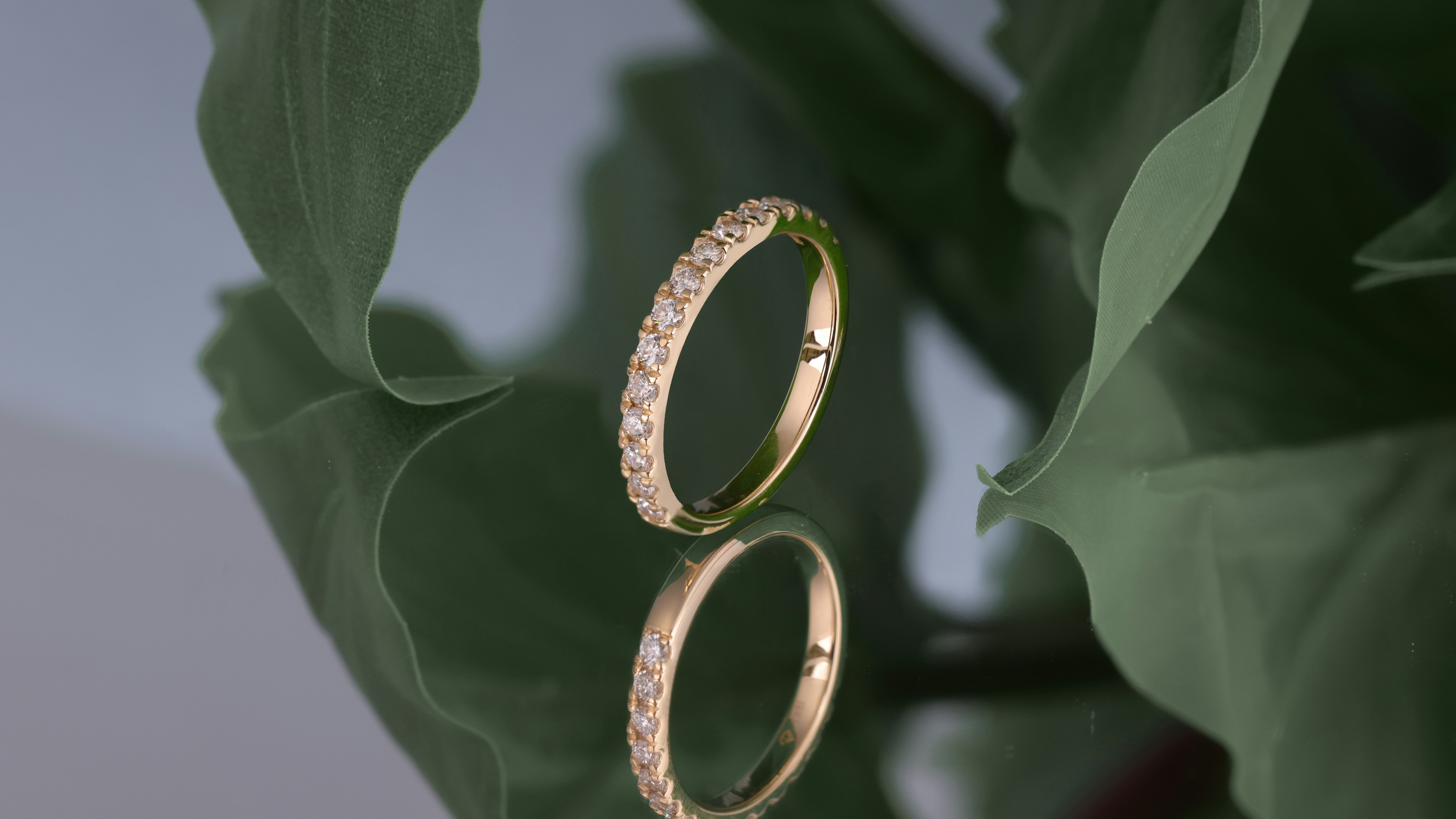 Gold Hoop Rings Adorned with Diamonds Reflected in Quiet Foliage