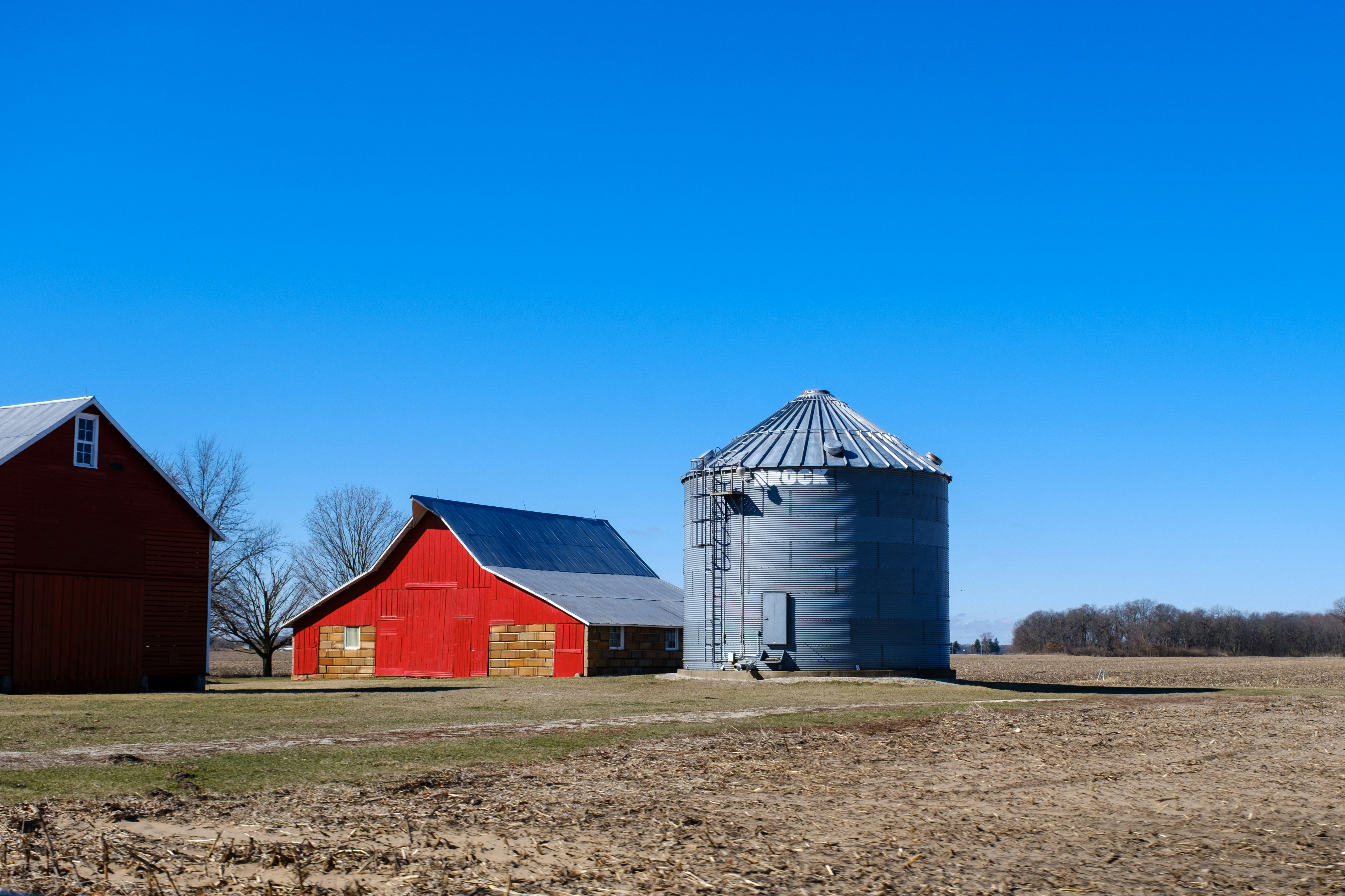 Red Barn, Silver Grain Bin: A Quiet Farmyard Under Wide Blue Skies