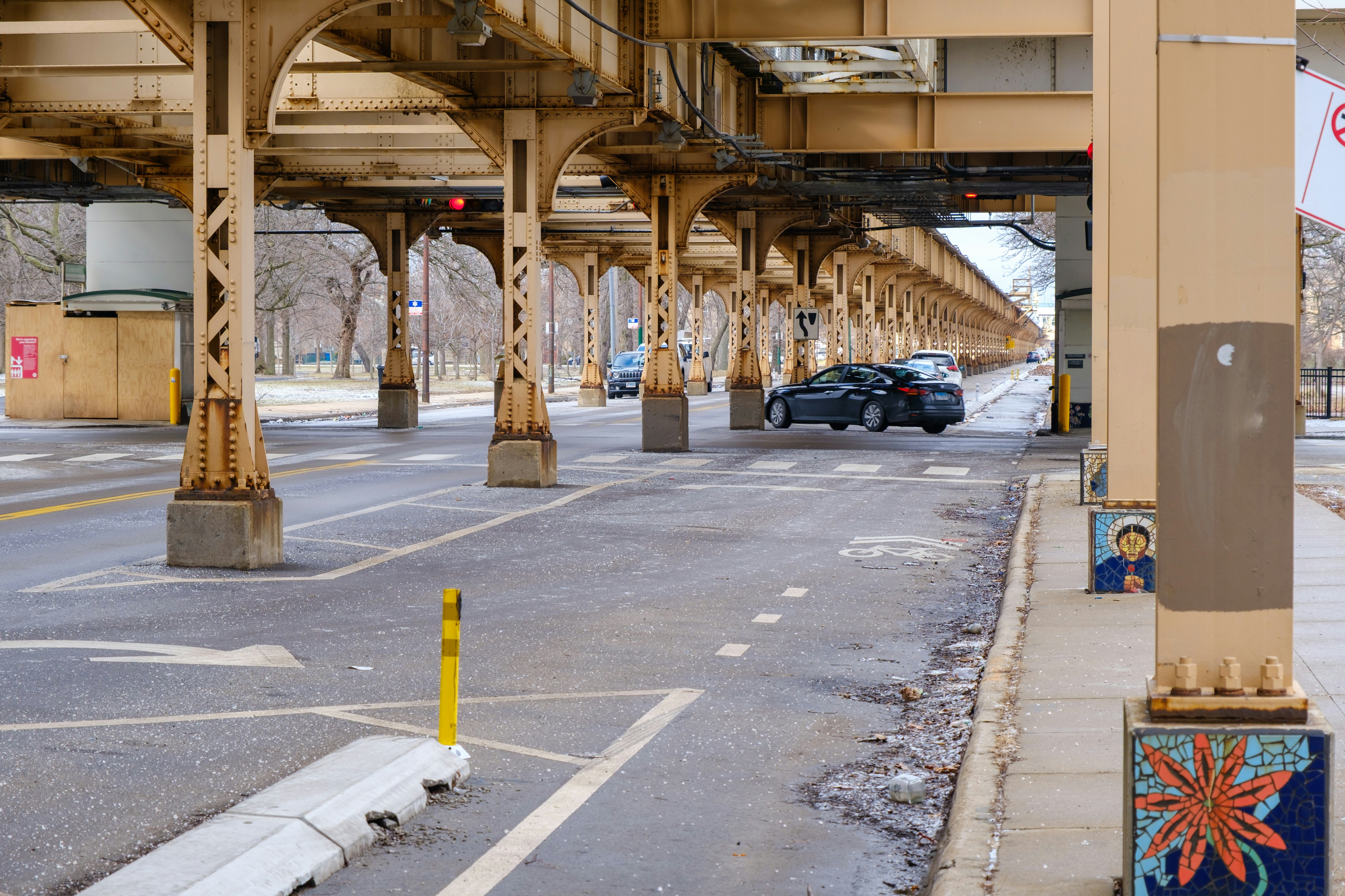 Under the Rusted Arches: A Quiet Street Scene with a Moving Car