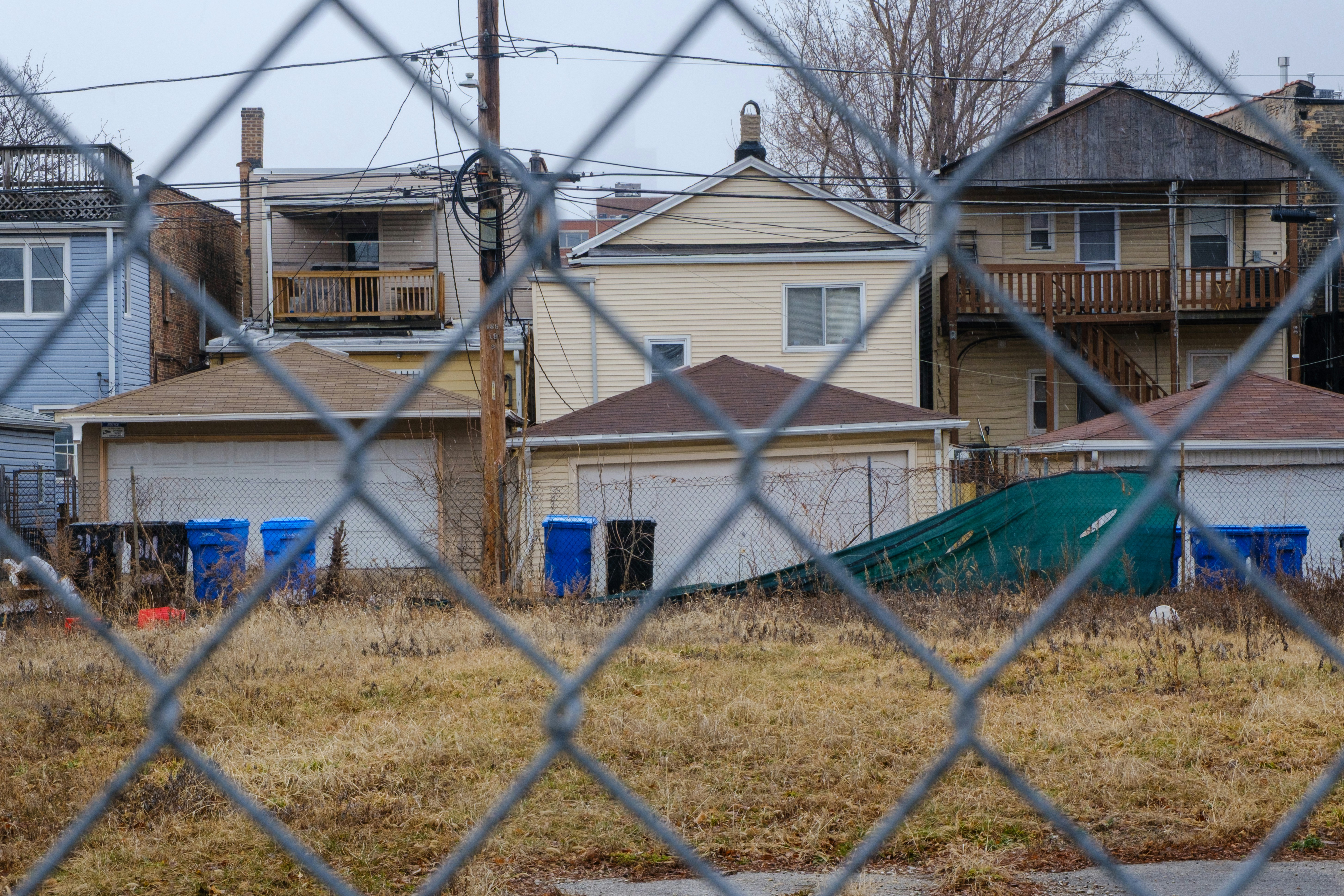 Through the Fence: Row of Suburban Homes Beyond a Chain-Link Veil
