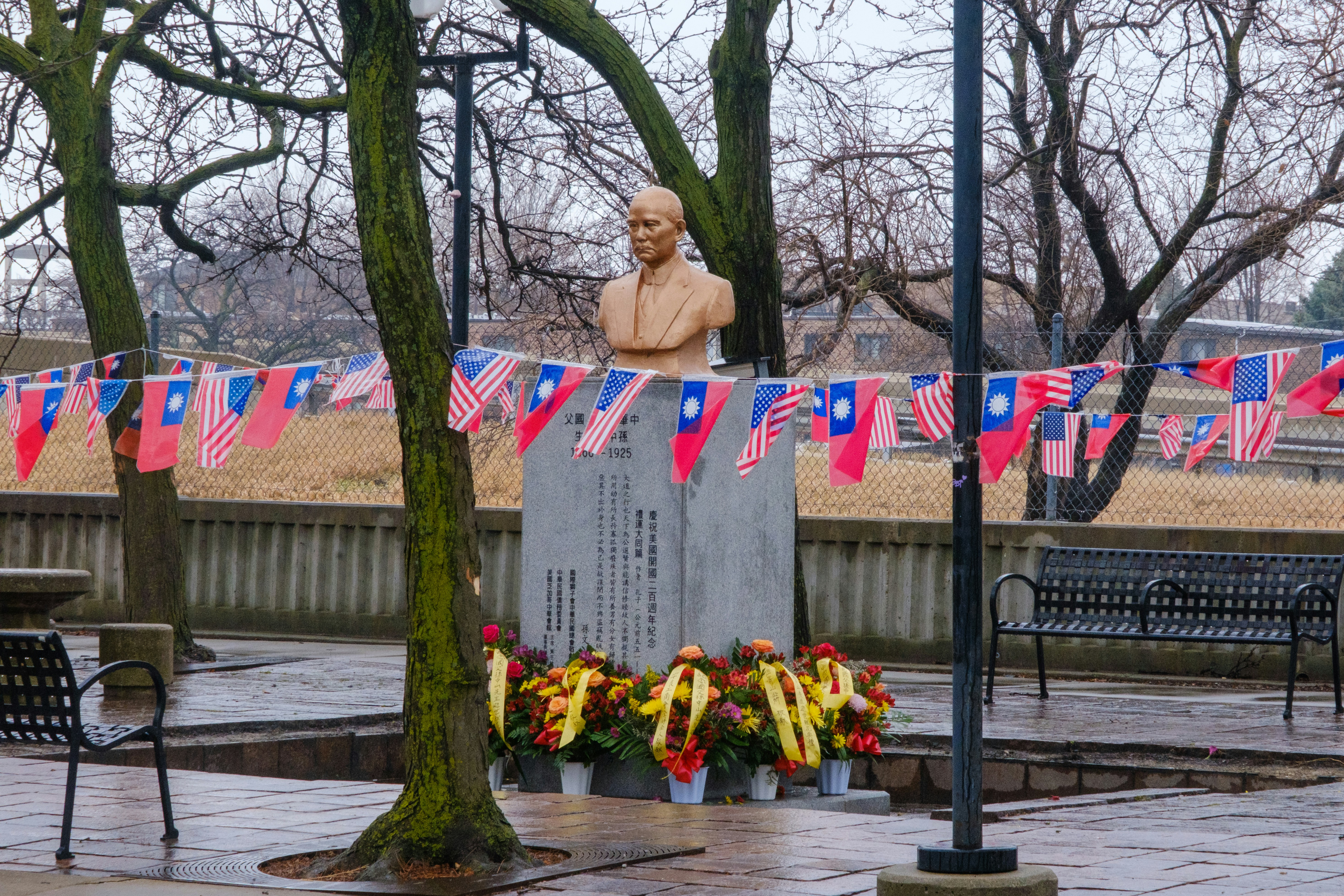 Bust of a Memory: Flag Garlanded Memorial in a Quiet Park