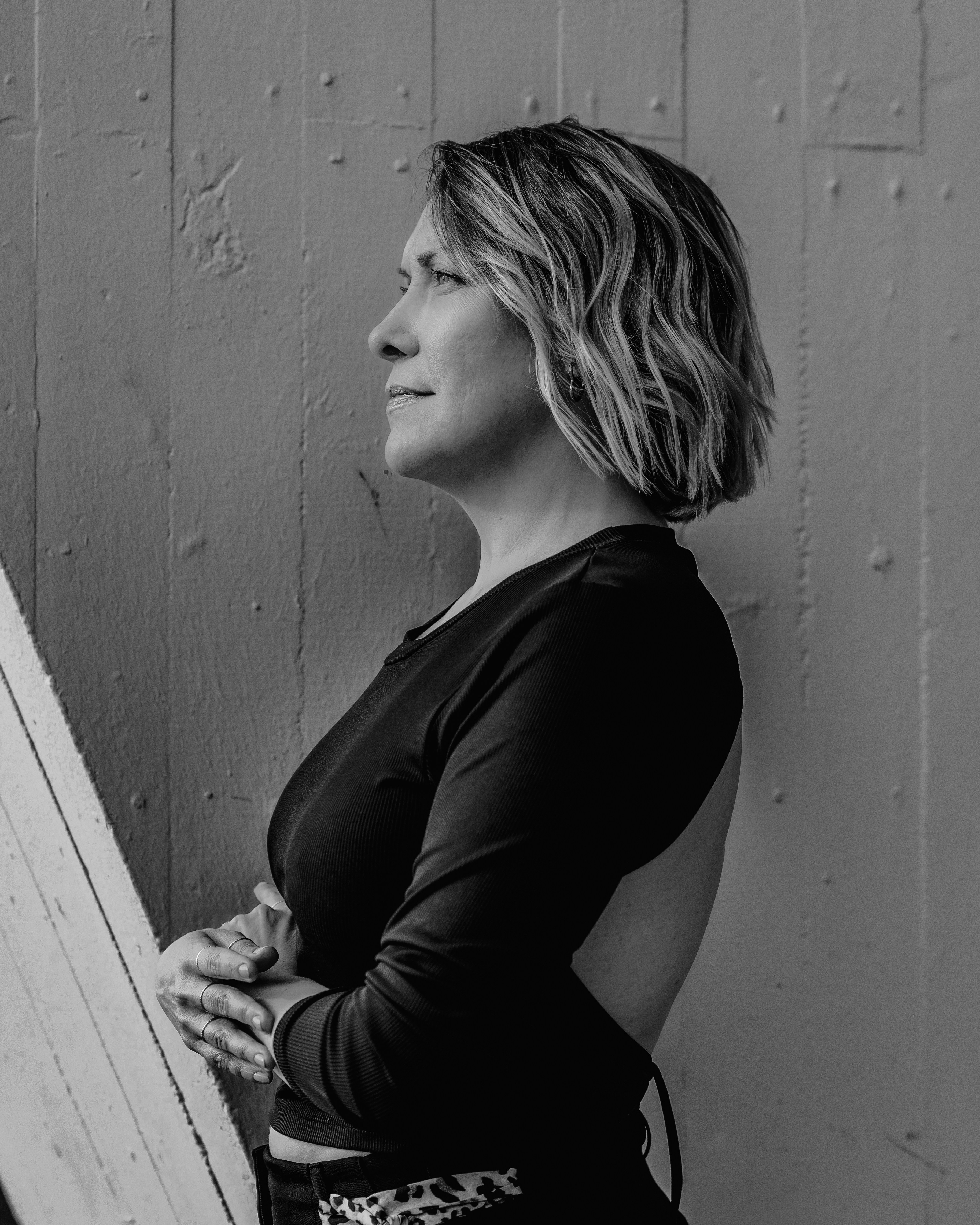 A woman with short hair in a black top against a textured wall
