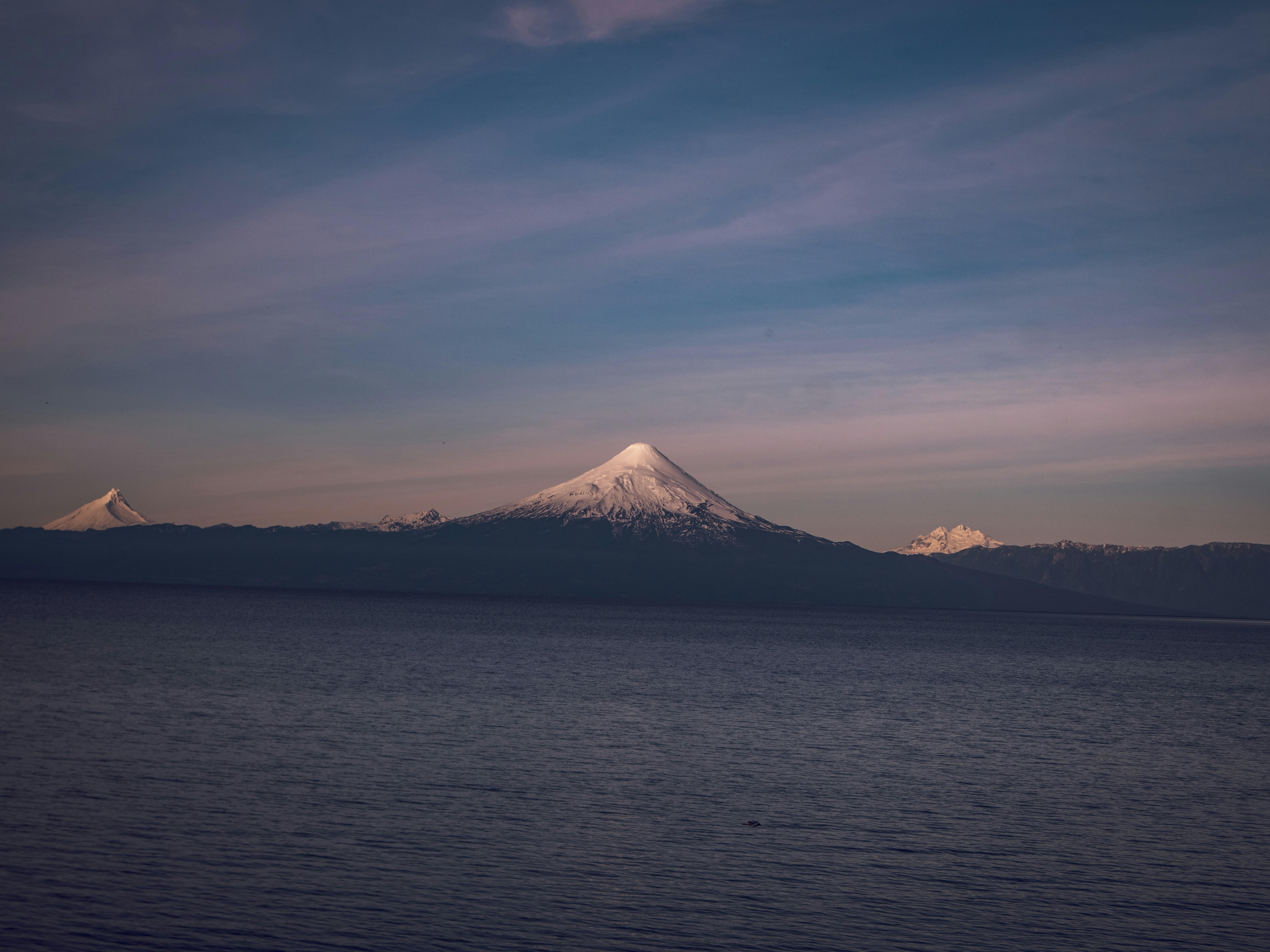 Twin Snow‑Capped Peaks Across a Calm Fjord