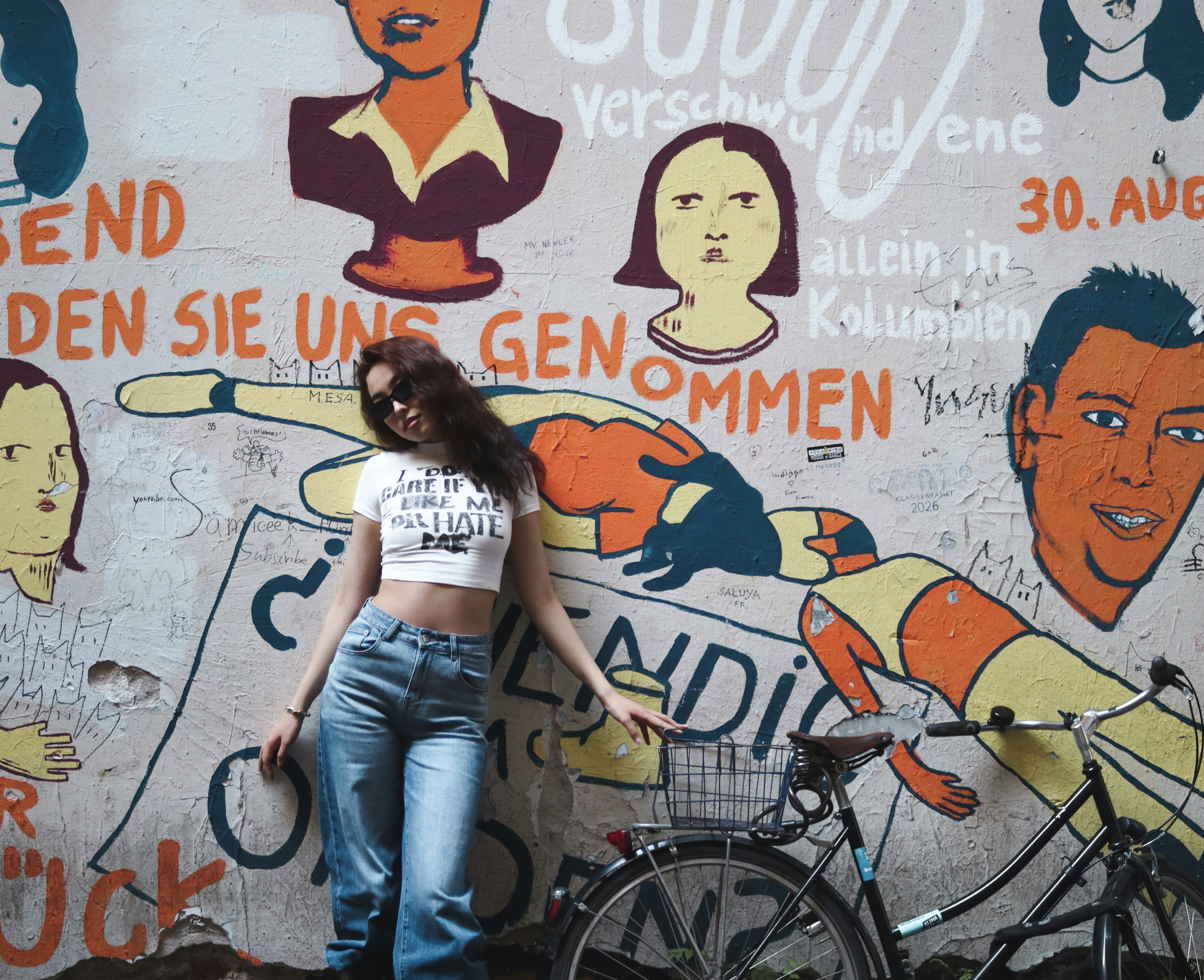 Graffiti Portraits and a Casual Strike: A Woman Poses by a Colorful Wall