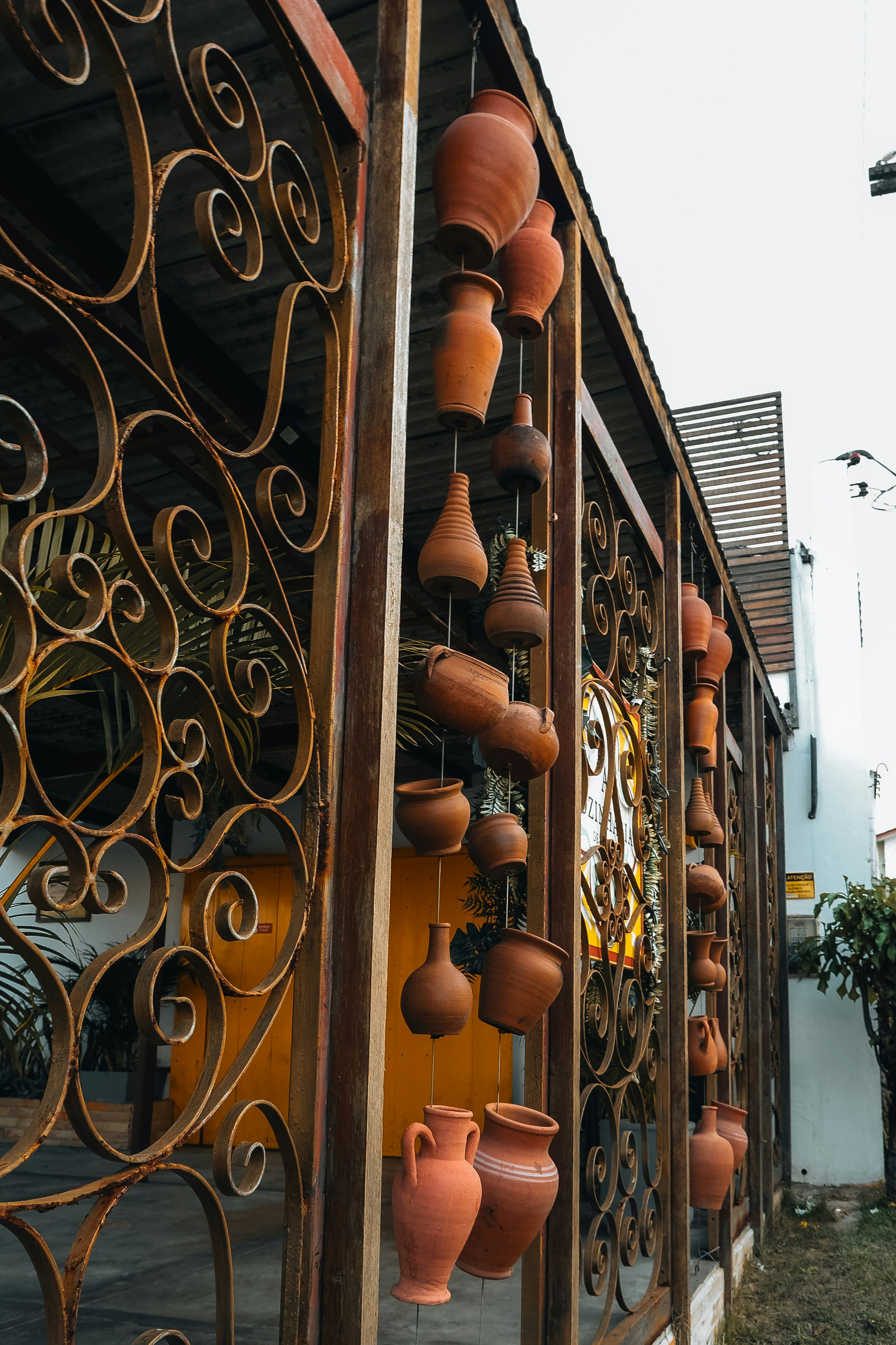Rust and Light: Ceramic Ornaments Dangle Along a Wrought Iron Corridor
