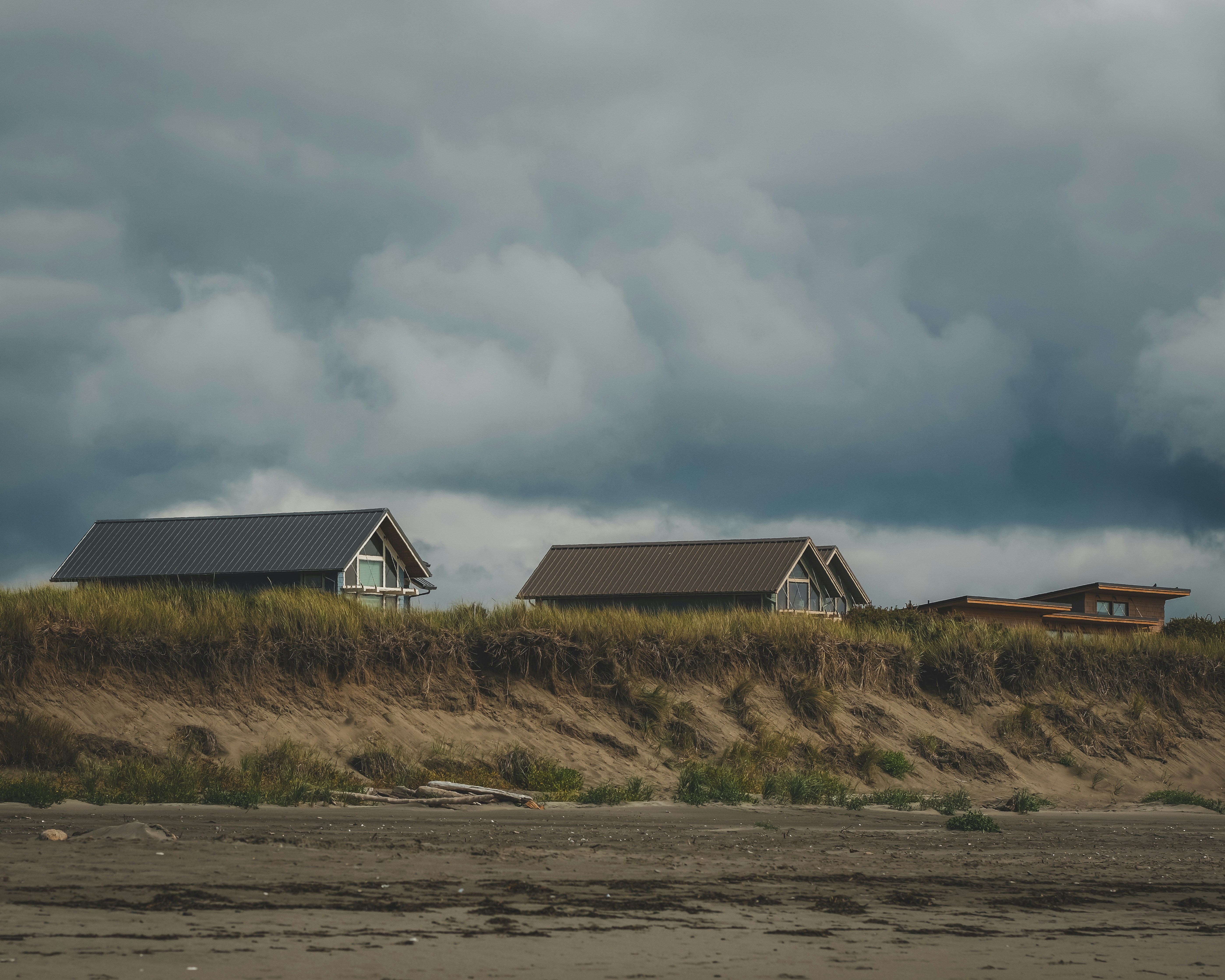 Coastal Dunes Retreat: A Trio of A-Frame Cabins Against Stormy Skies