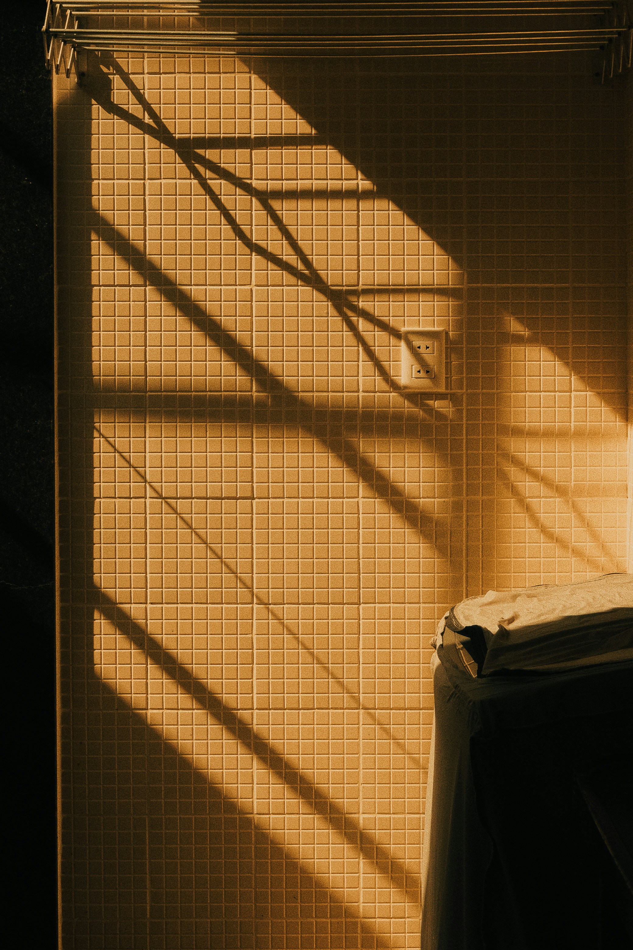 Sunlit Grid Shadows Cast Across a Quiet Tile Laundry Space