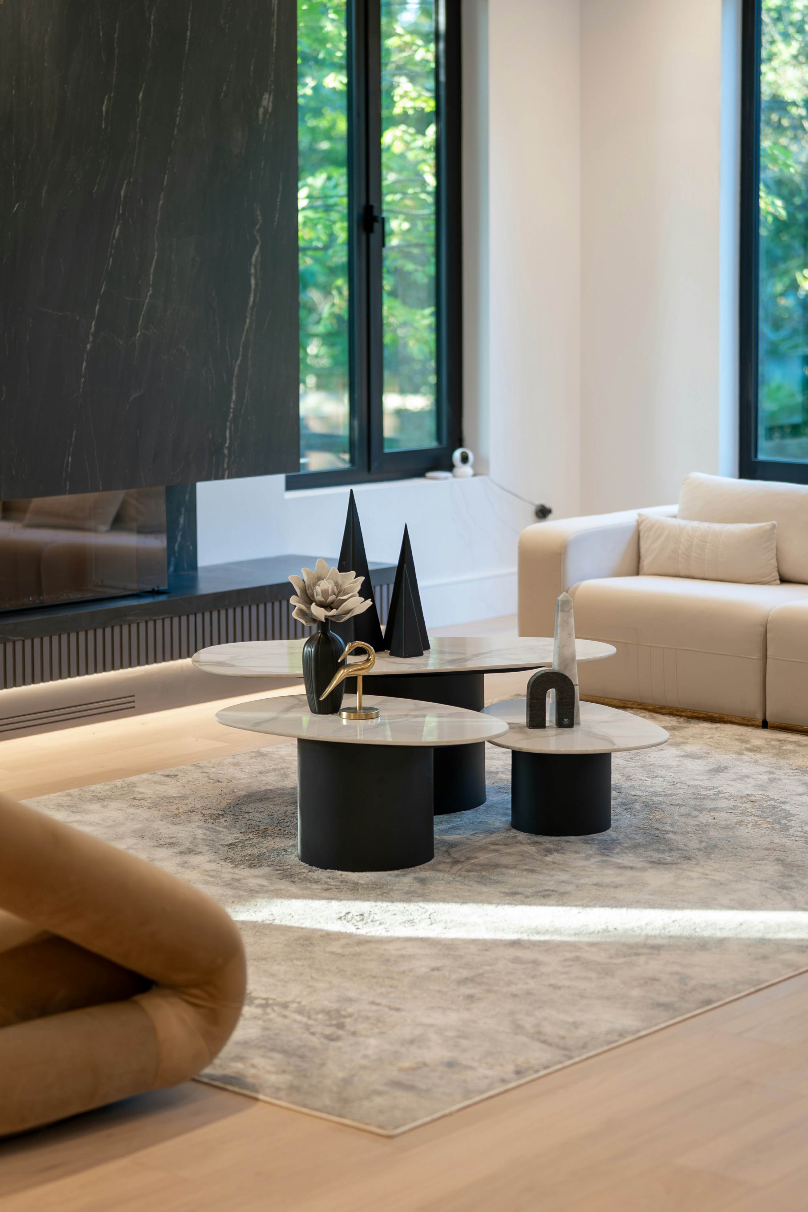 Three tiered marble coffee tables with black bases in a modern living room