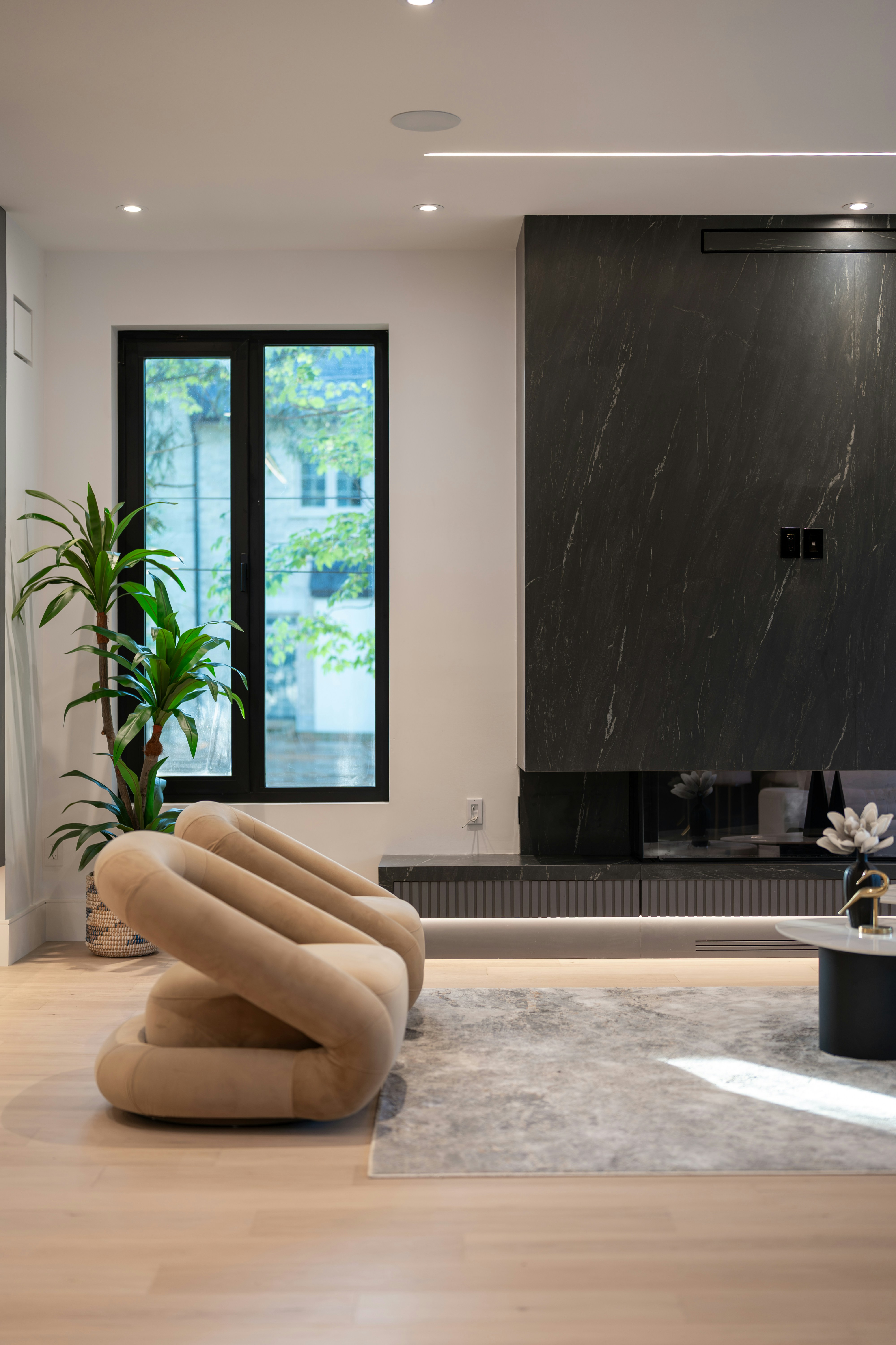 Sculptural Lounge: Soft Tan Seating by the Black Marble Hearth