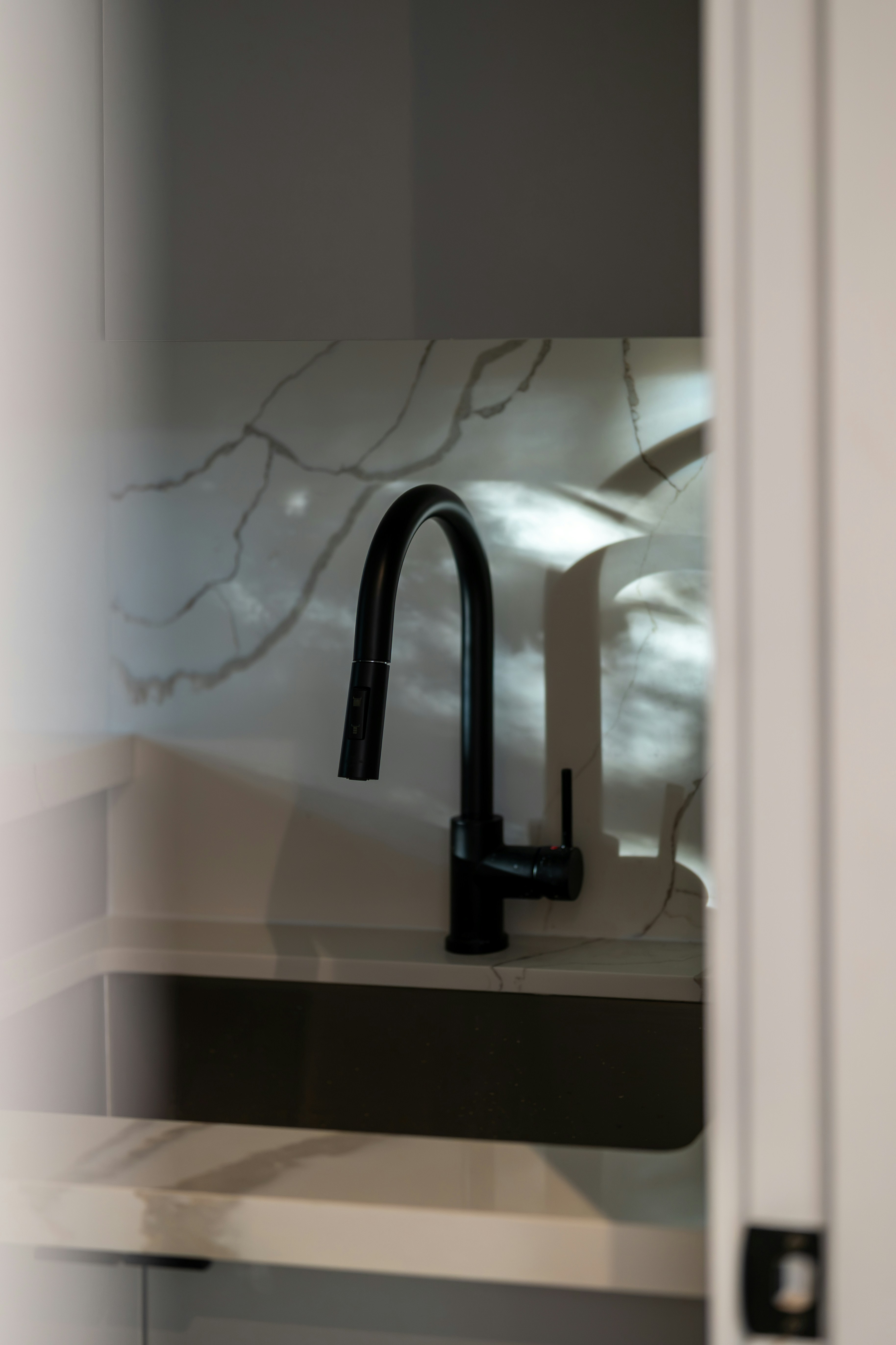 Minimalist Kitchen Tap: A Matte Black Faucet Under Marble Veins