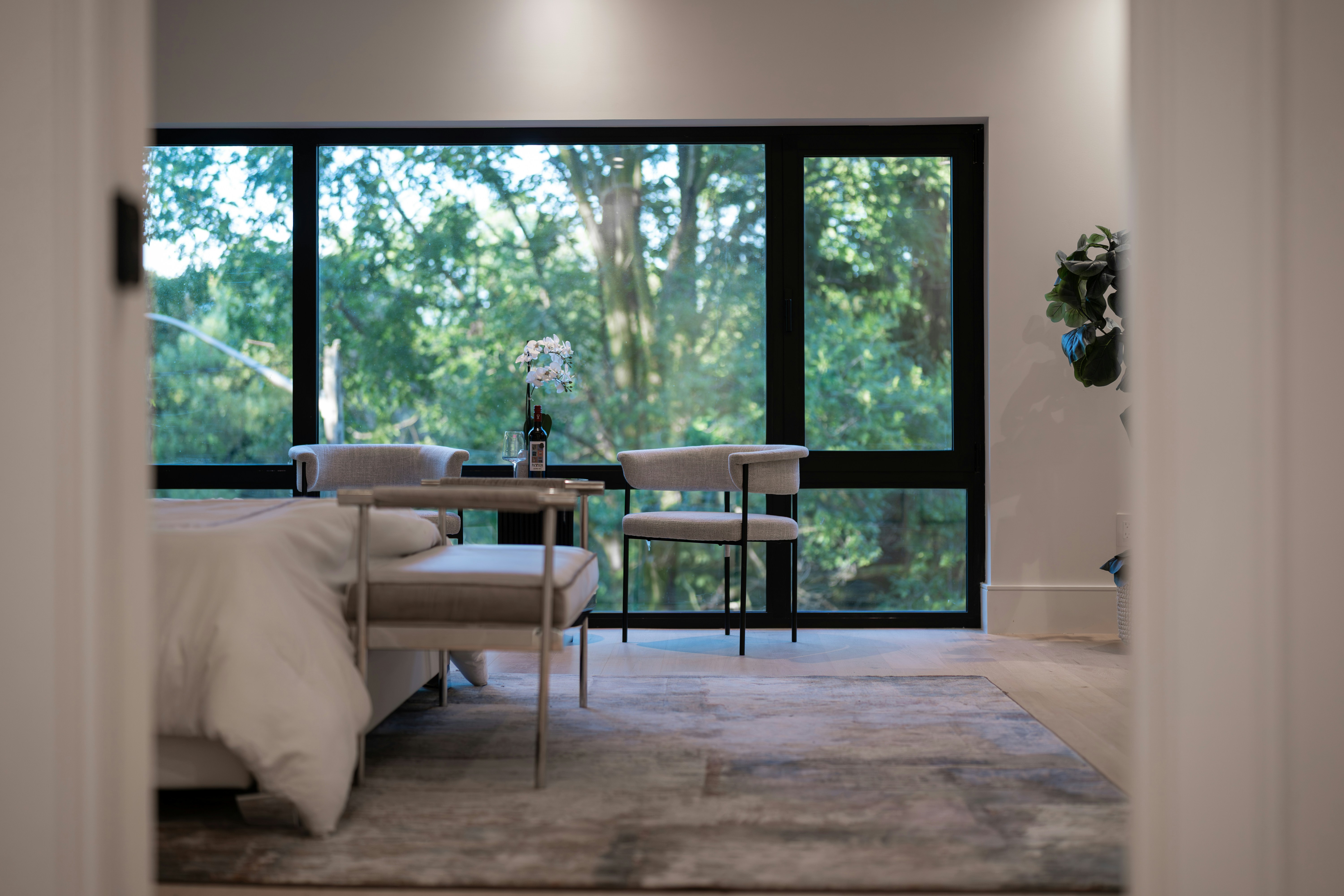 Bright hotel suite with floor-to-ceiling windows and a wine on the desk