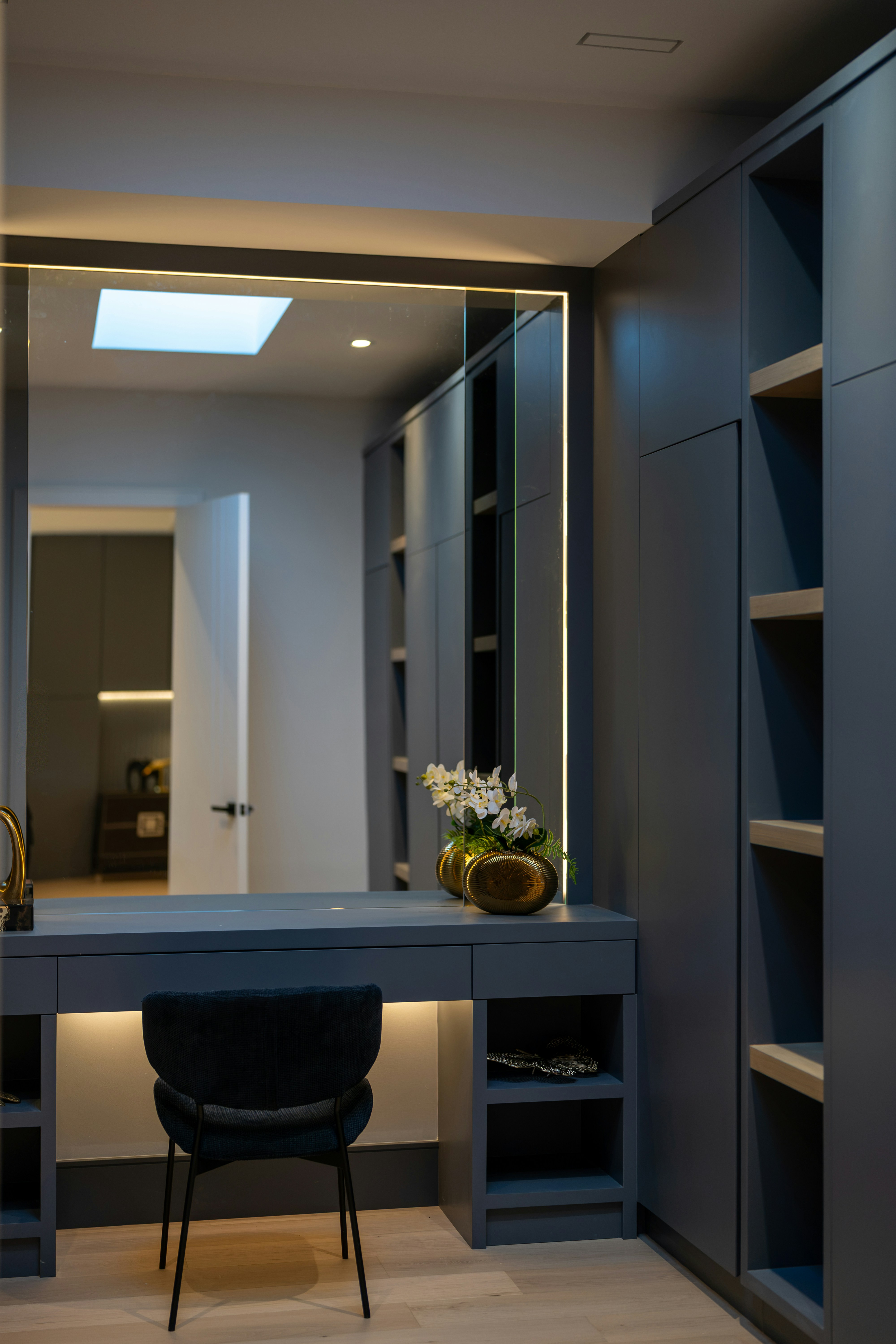 A dark blue vanity with a mirror and chair in a modern bedroom