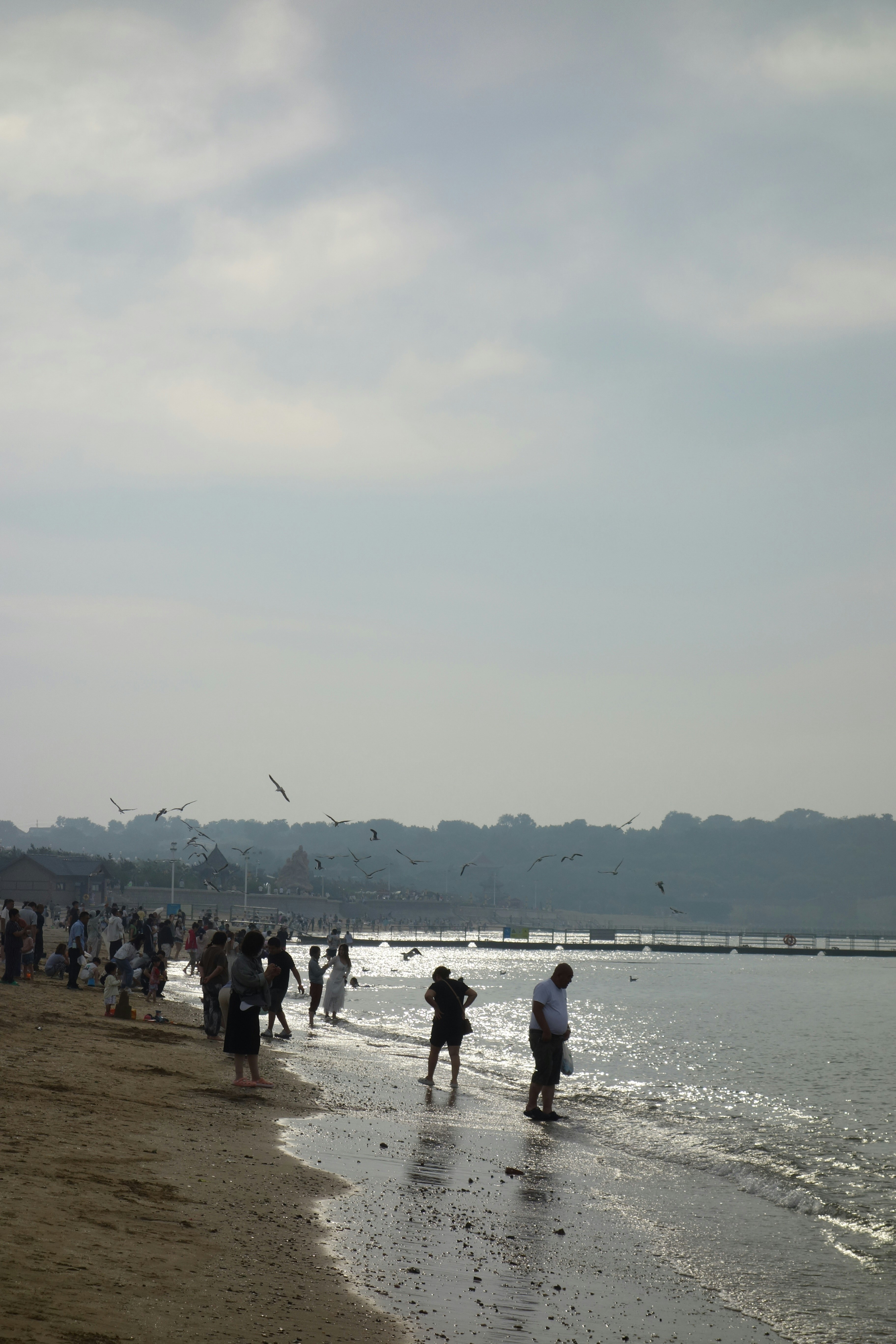 Dawn on the Seaside Parade: People along the Shore Under a Soft Sky