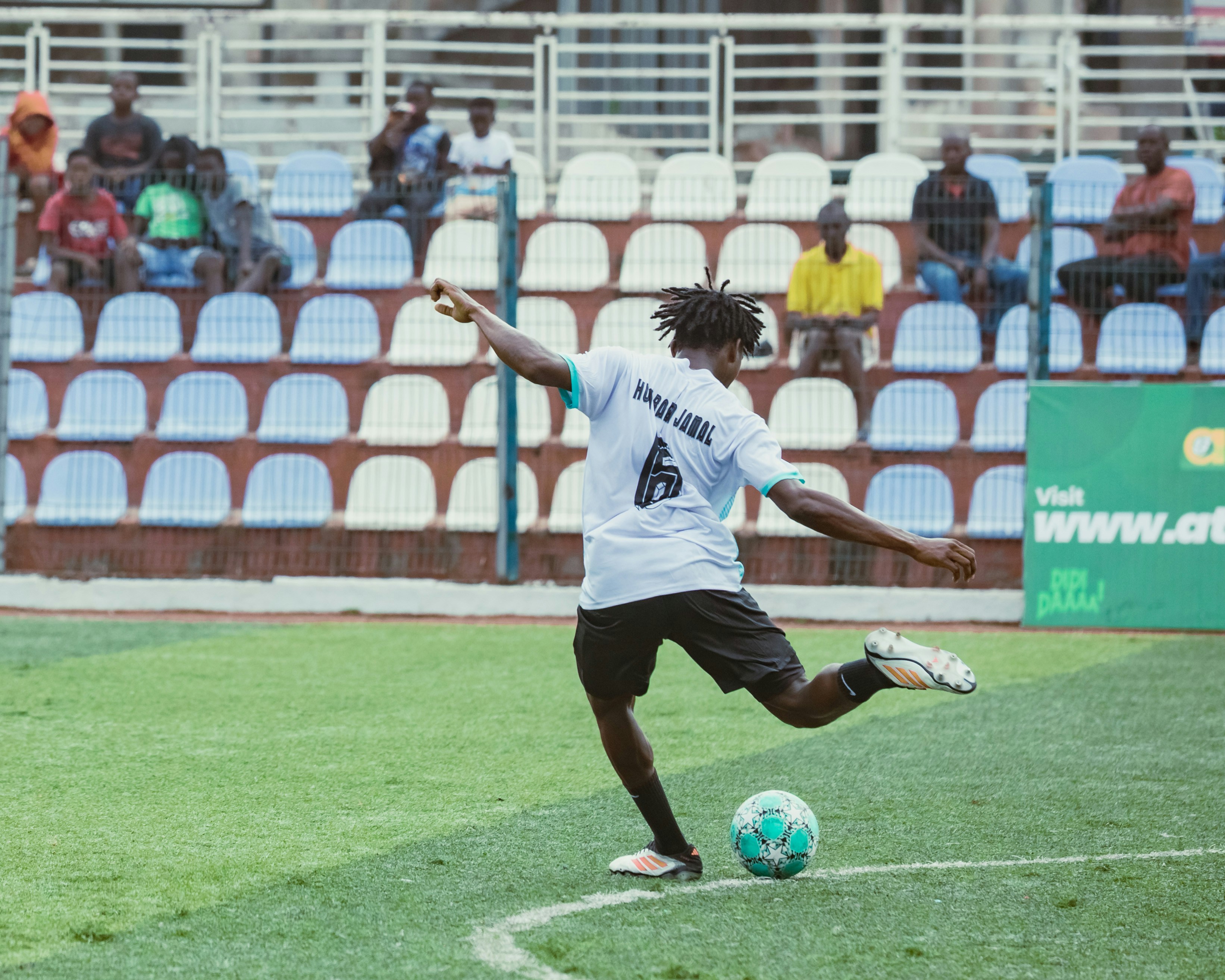 Midfield Moment: Player in Motion Strikes the Ball Across a Green Crown