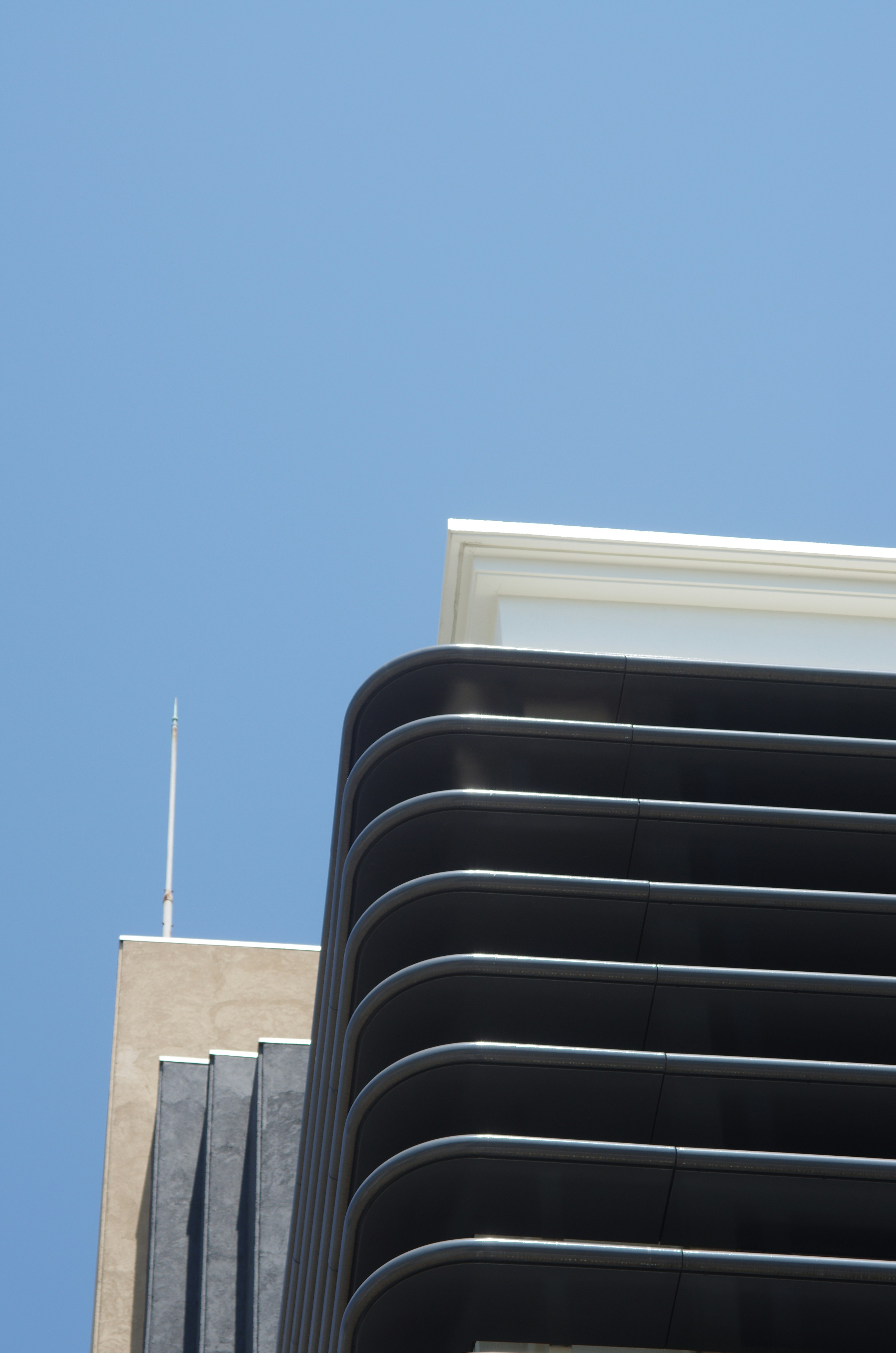 Curtained Edges: A Modern Facade Bursts from a Calm Blue Sky
