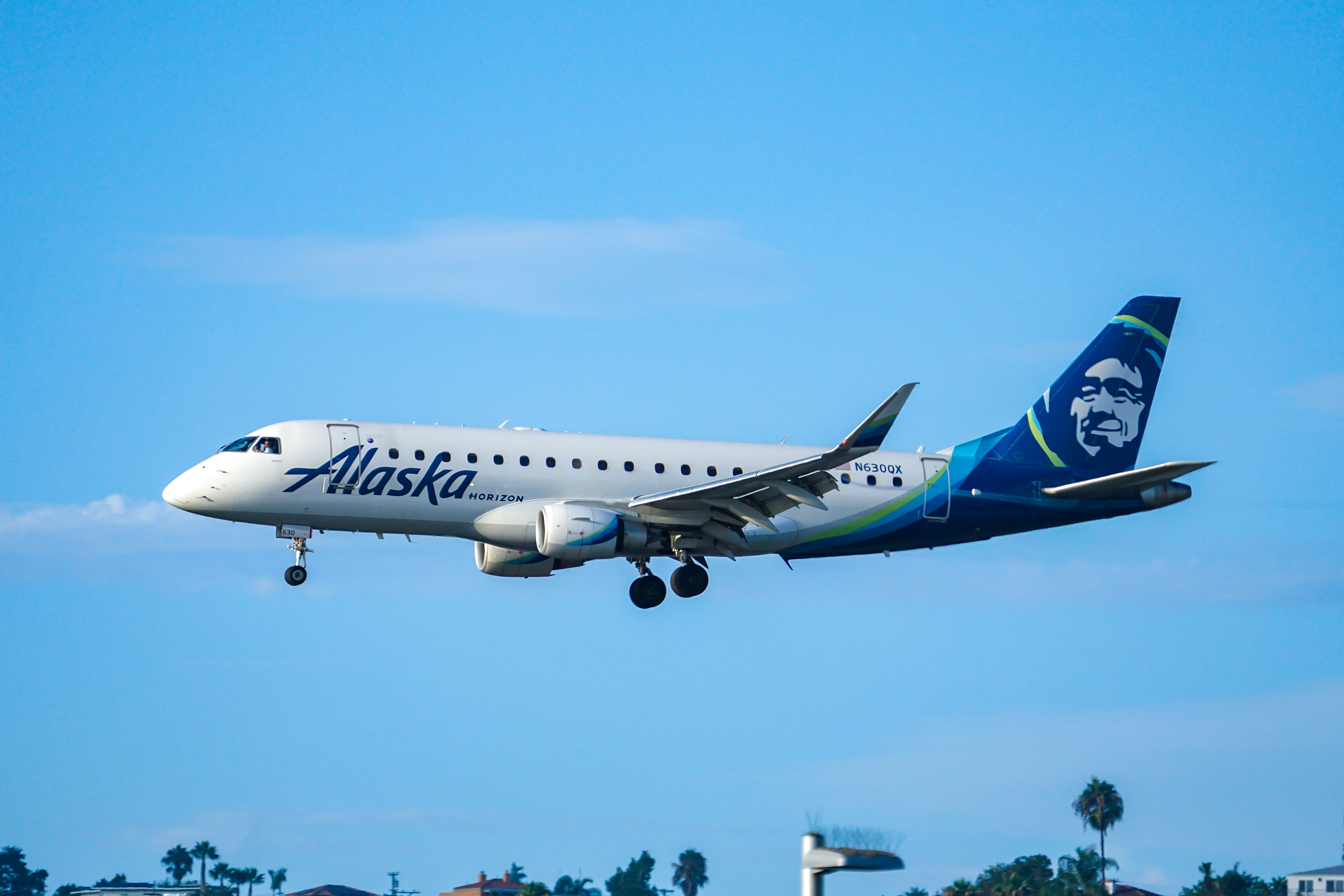 Alaska Airlines A320 in mid-landing against a clear blue sky